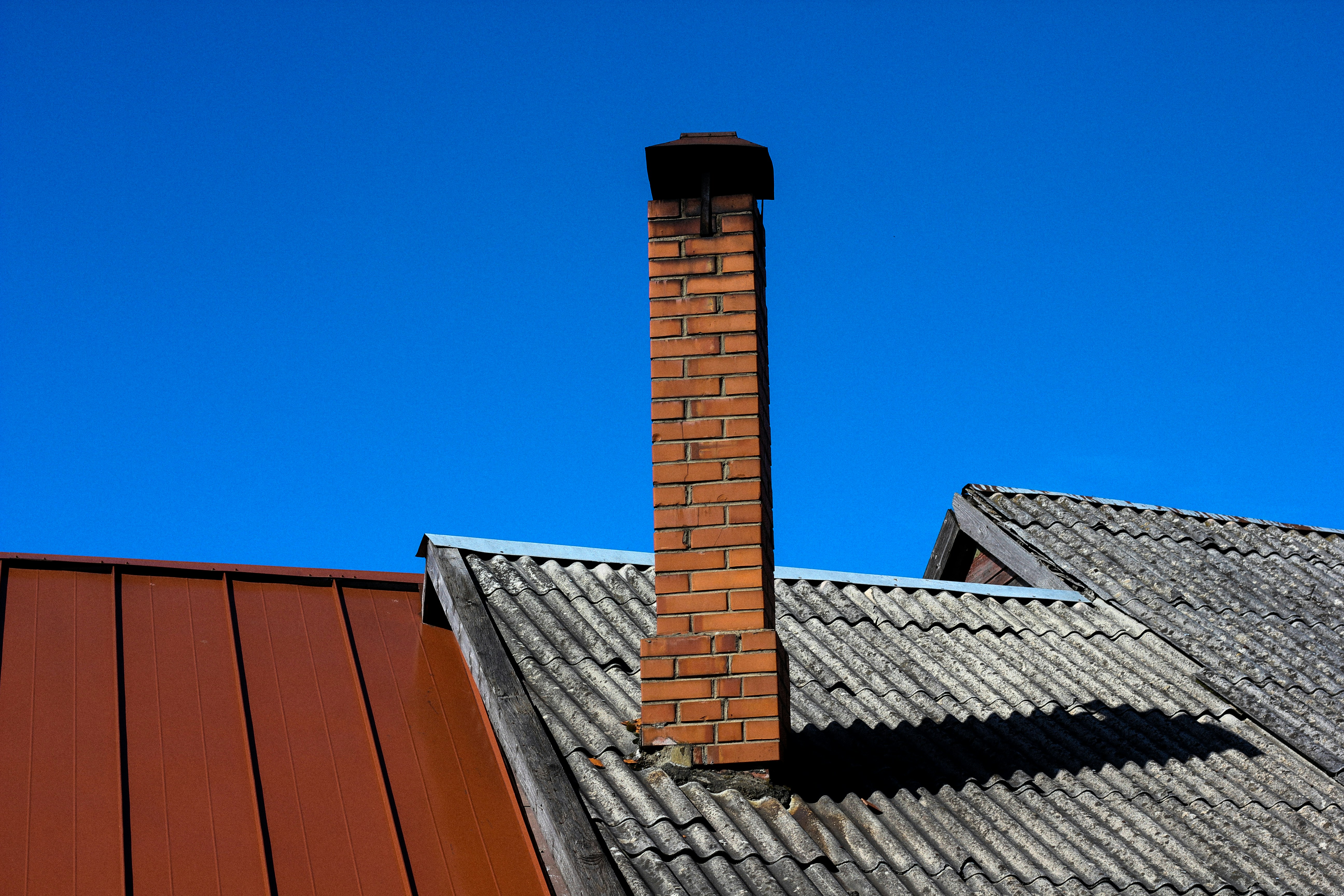 Brick chimney on a rooftop under blue sky