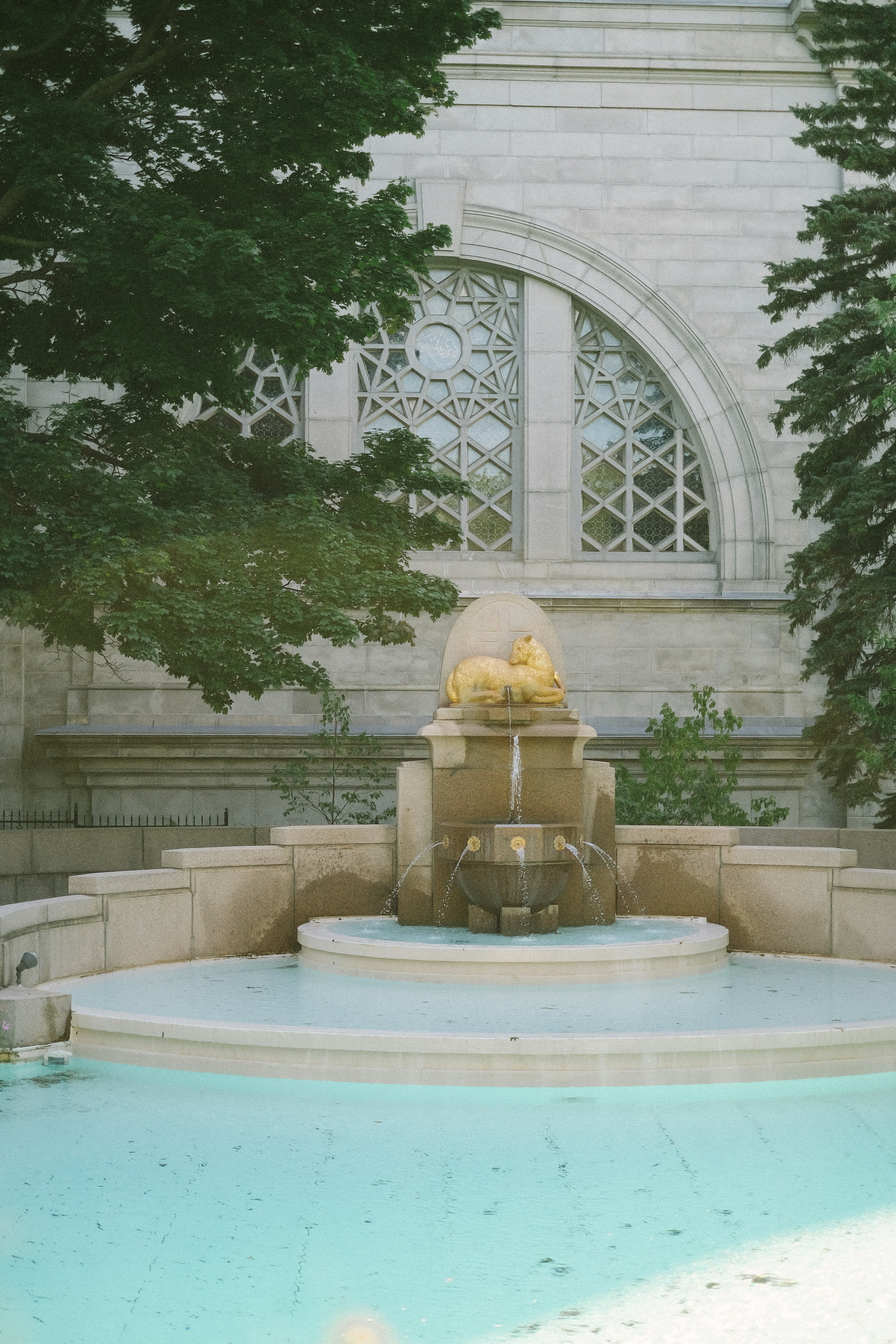 The Paschal Lamb fountain at St. Joseph's Oratory in Montreal, Quebec. | A stone fountain with a lion statue in front of a building.