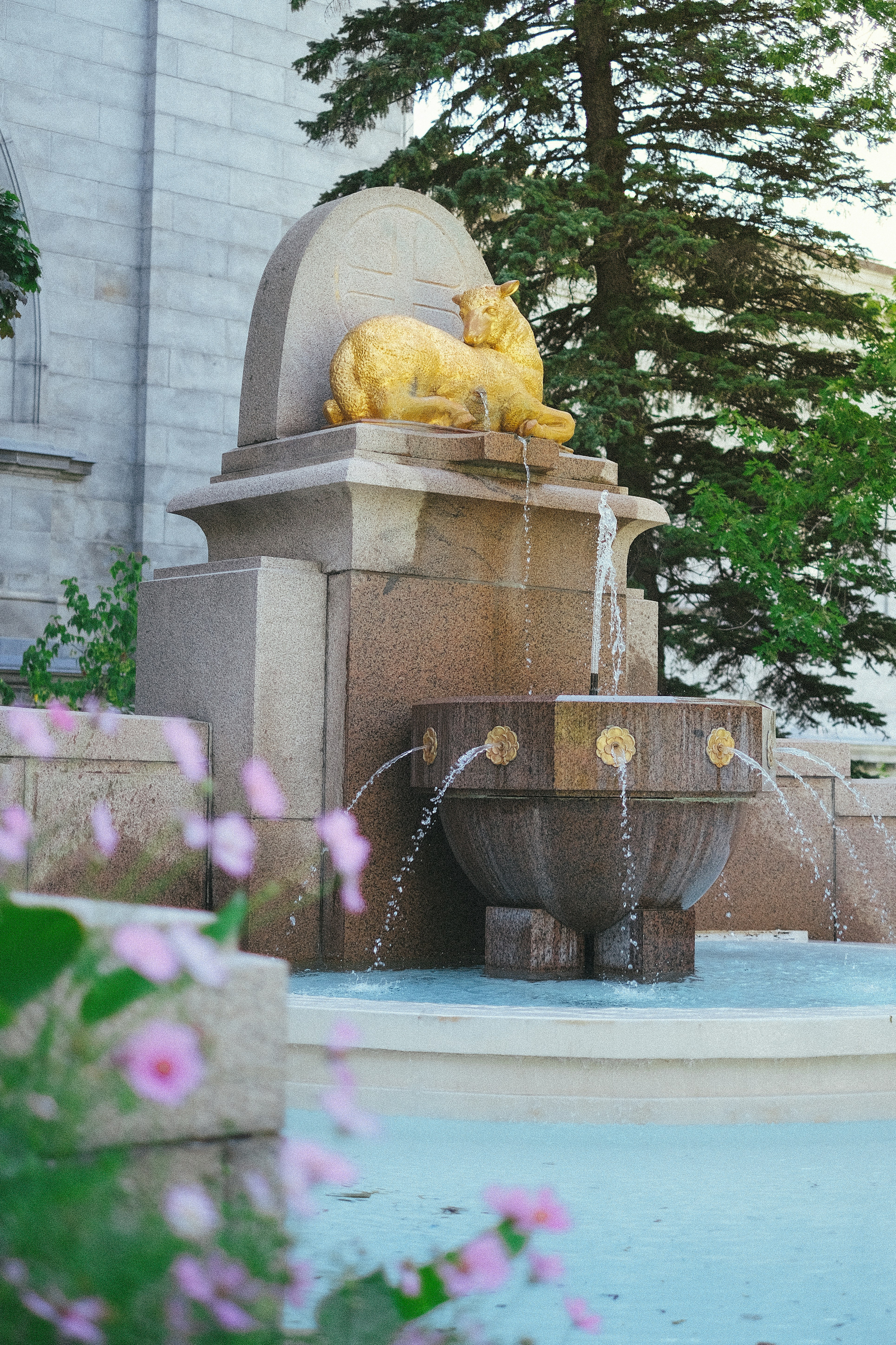 The Paschal Lamb fountain at St. Joseph's Oratory in Montreal, Quebec. | Golden lion statue atop a stone fountain with water flowing.