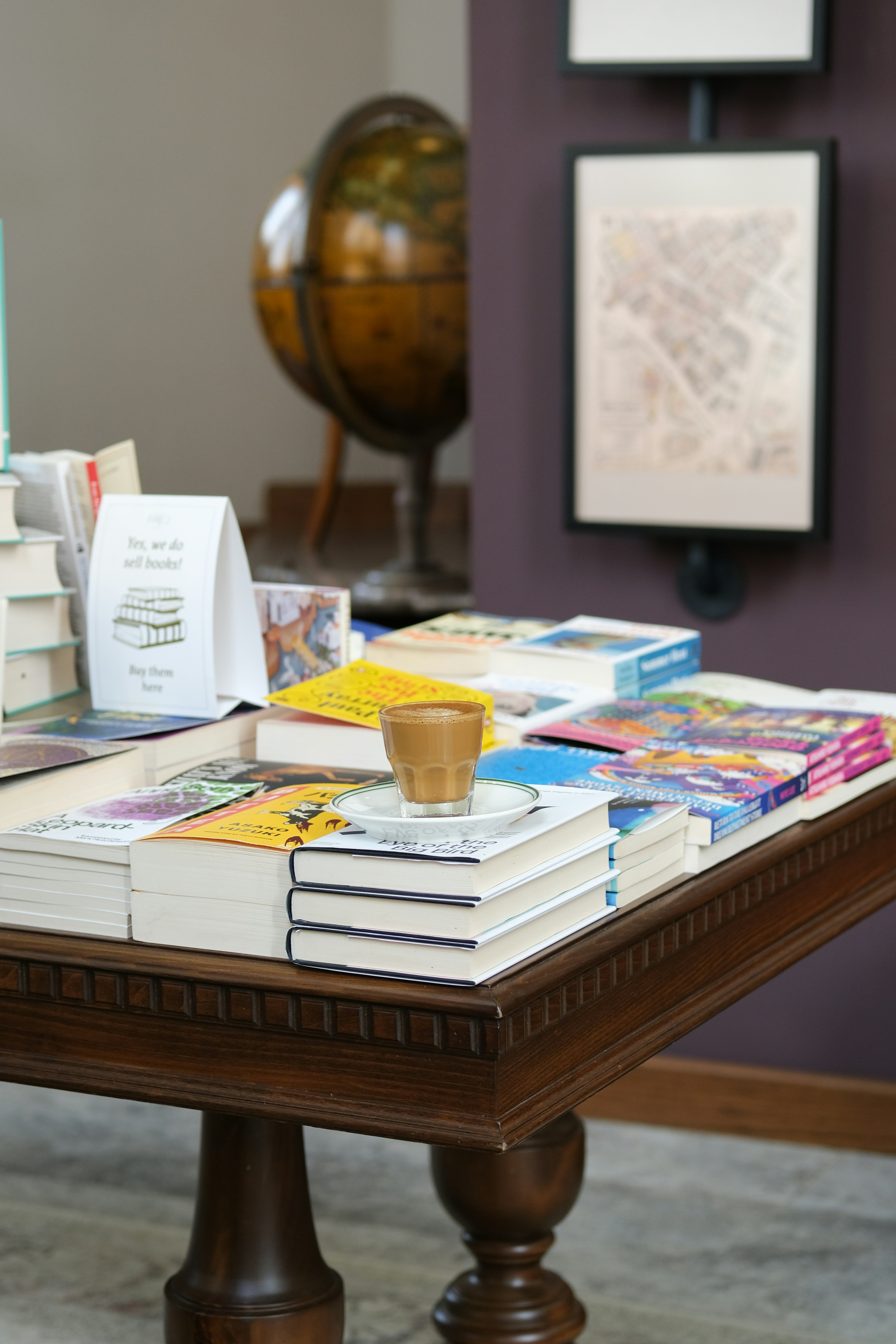 Books and a small cup on a wooden table.