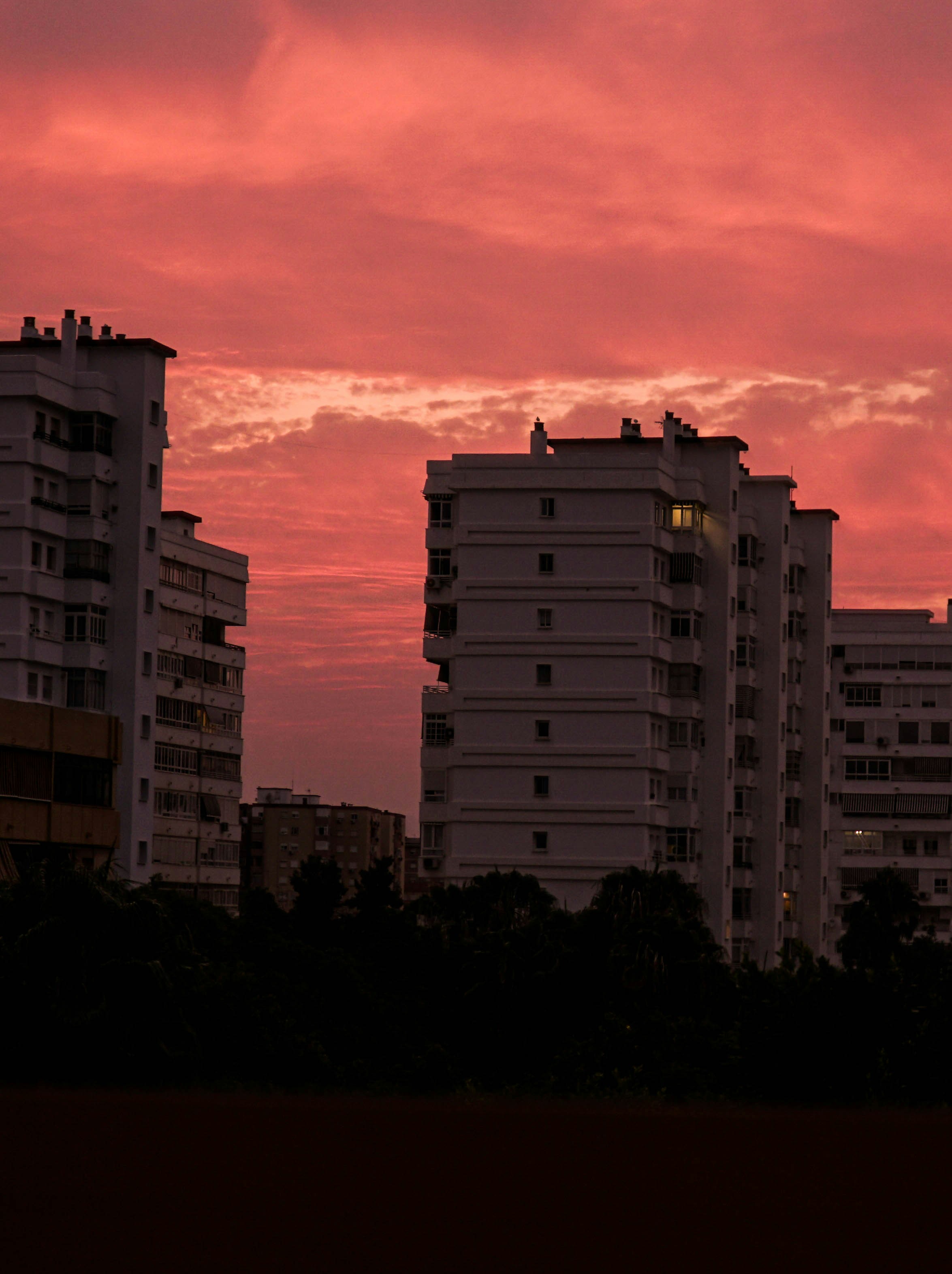 Apartment buildings silhouetted against a dramatic pink sky.