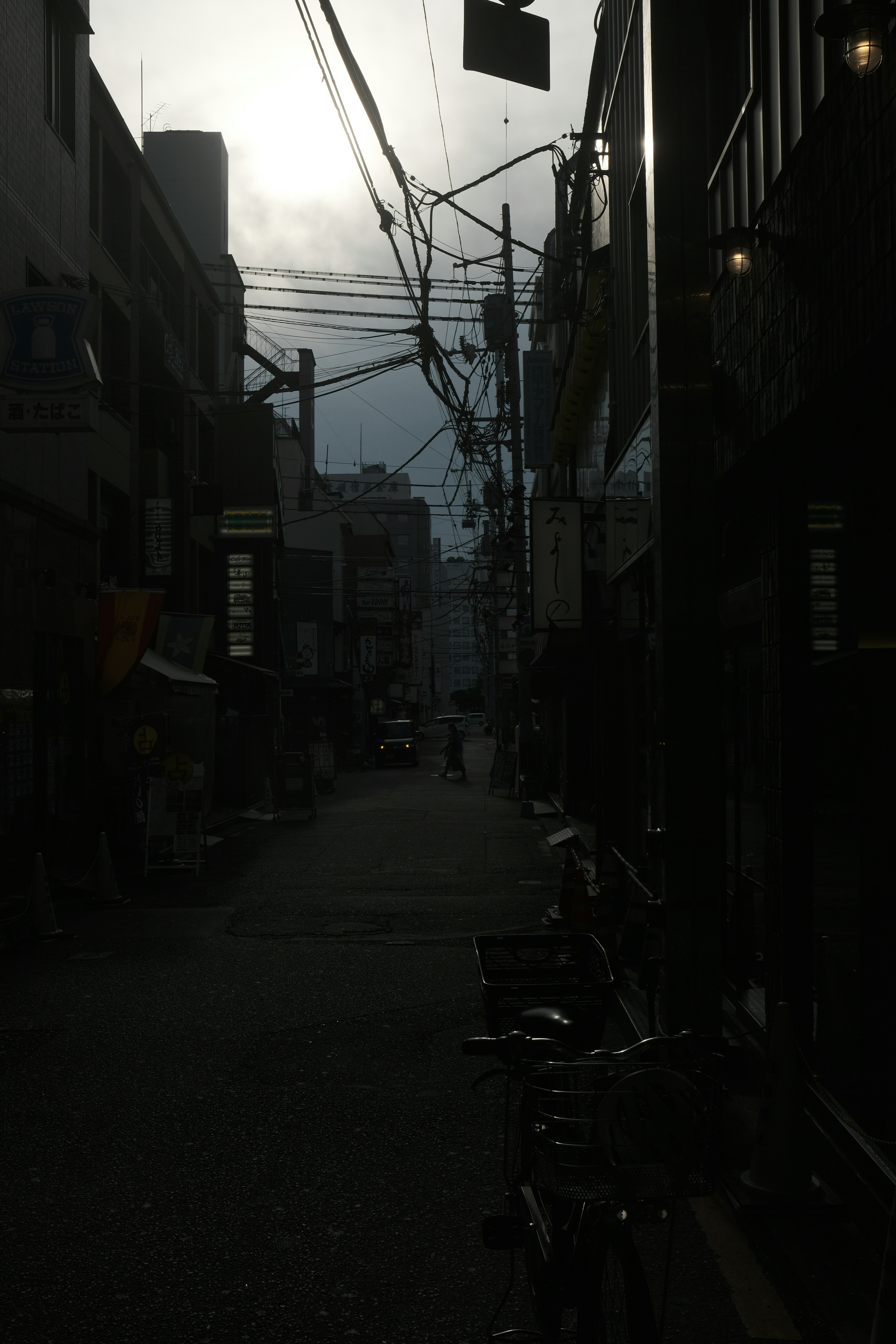 Dim alleyway with overhead wires and parked bicycles
