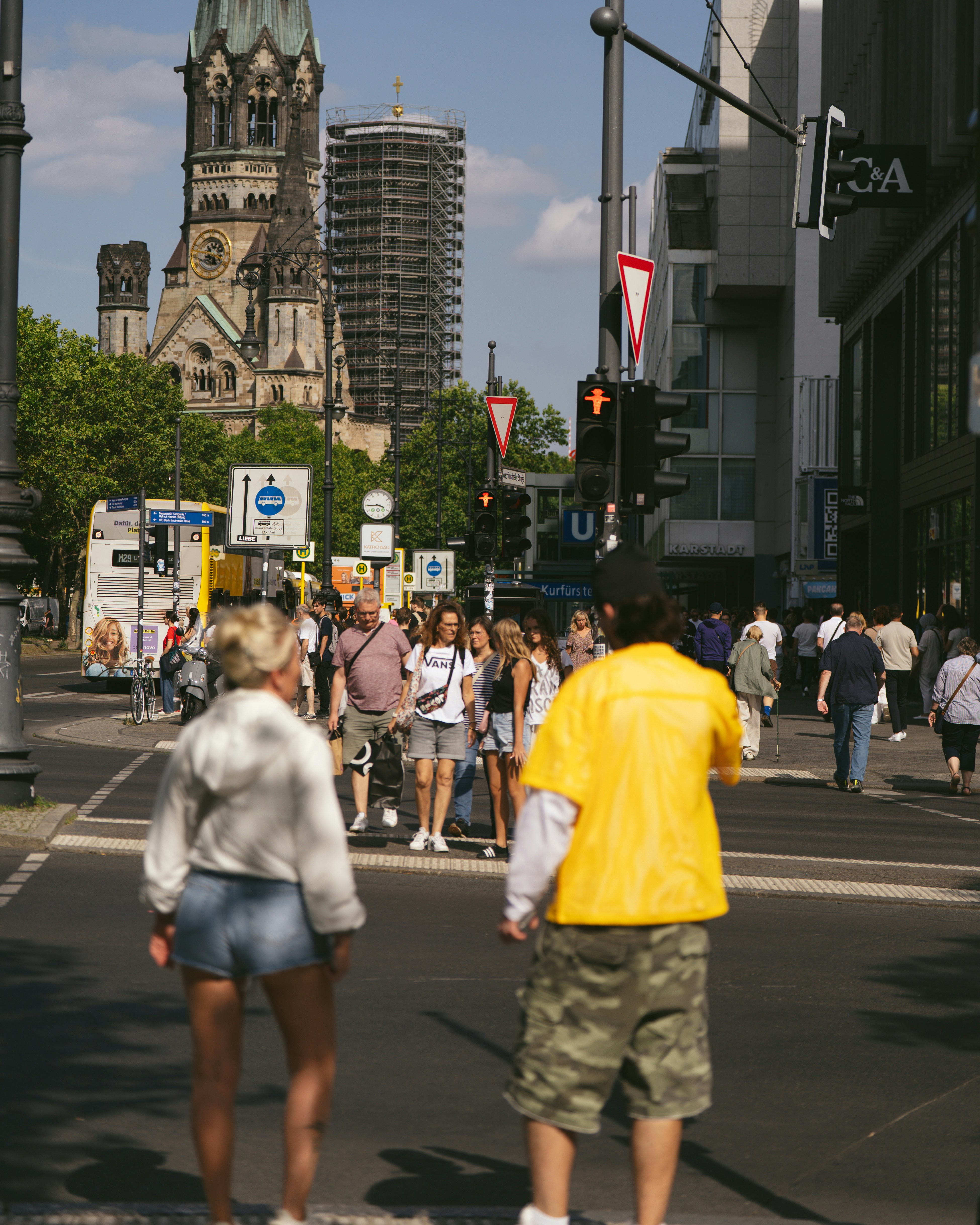Crowd of pedestrians navigating a bustling street with a historic church in the background, showcasing a blend of modern life and architectural heritage.