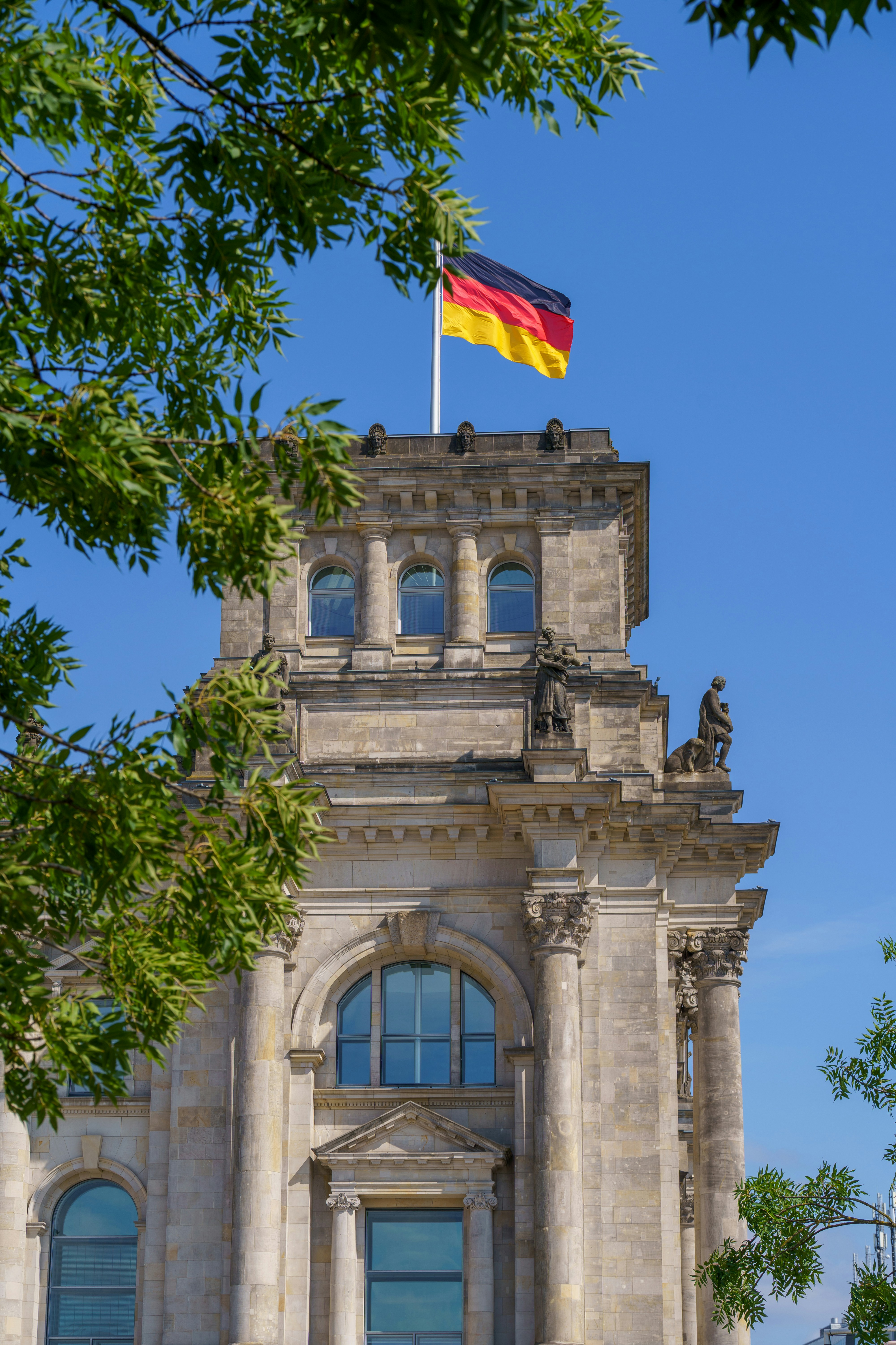 Flag Over a Neoclassical Facade: Sunlit Stone Under a Clear Blue Sky