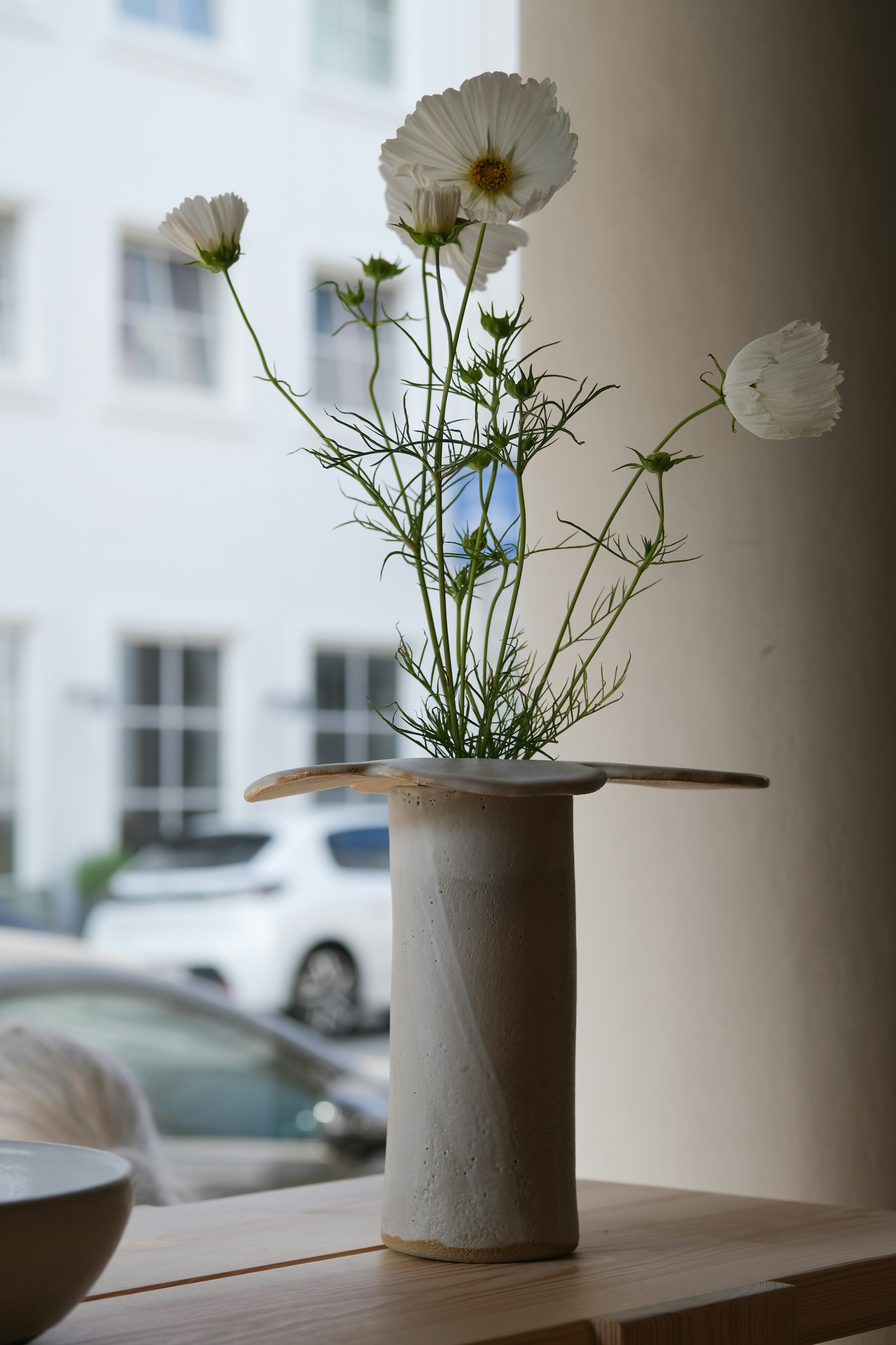 Delicate white flowers in a minimalist vase, showcasing a blend of natural beauty and handcrafted artistry.