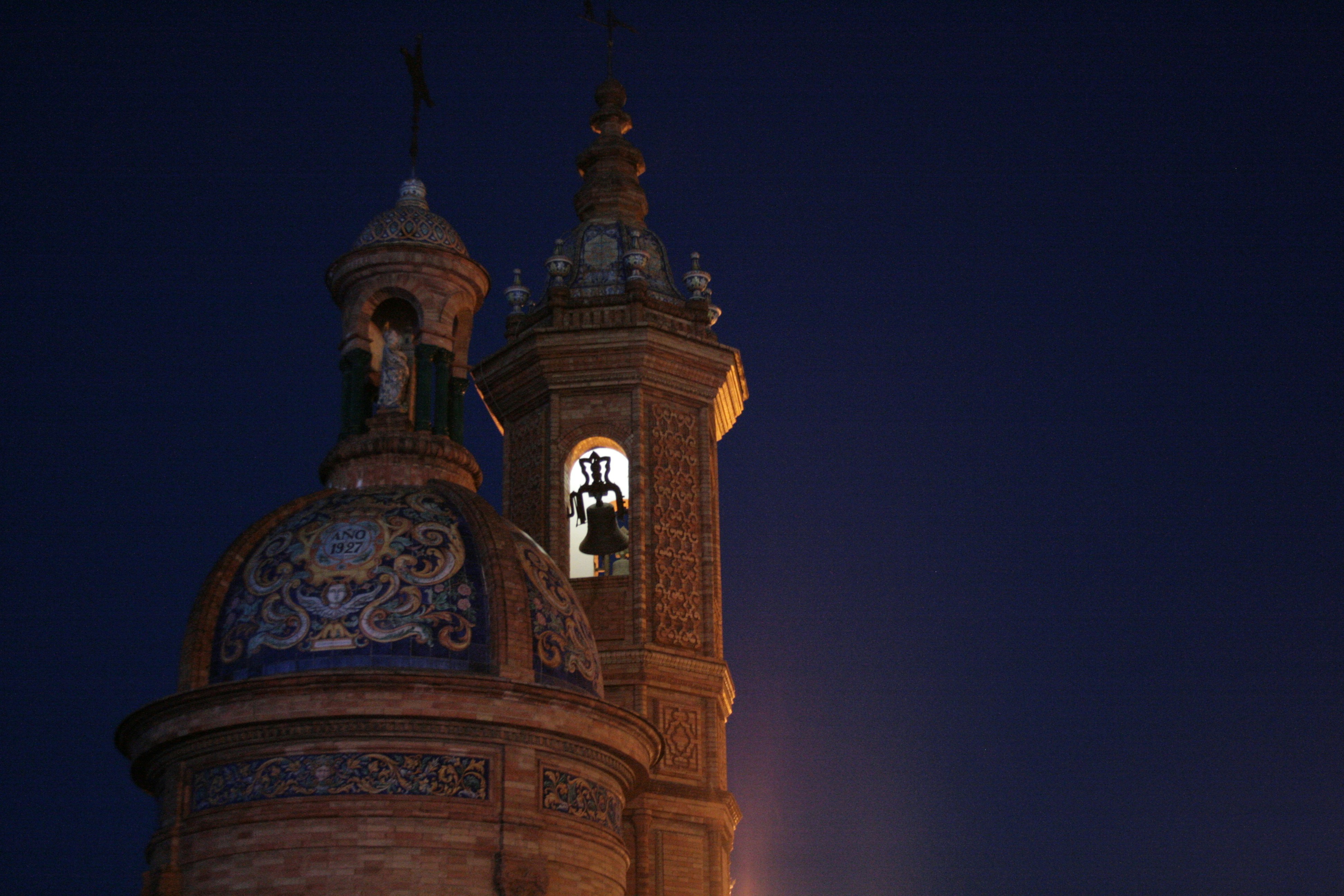 Ornate tower with bell illuminated against night sky