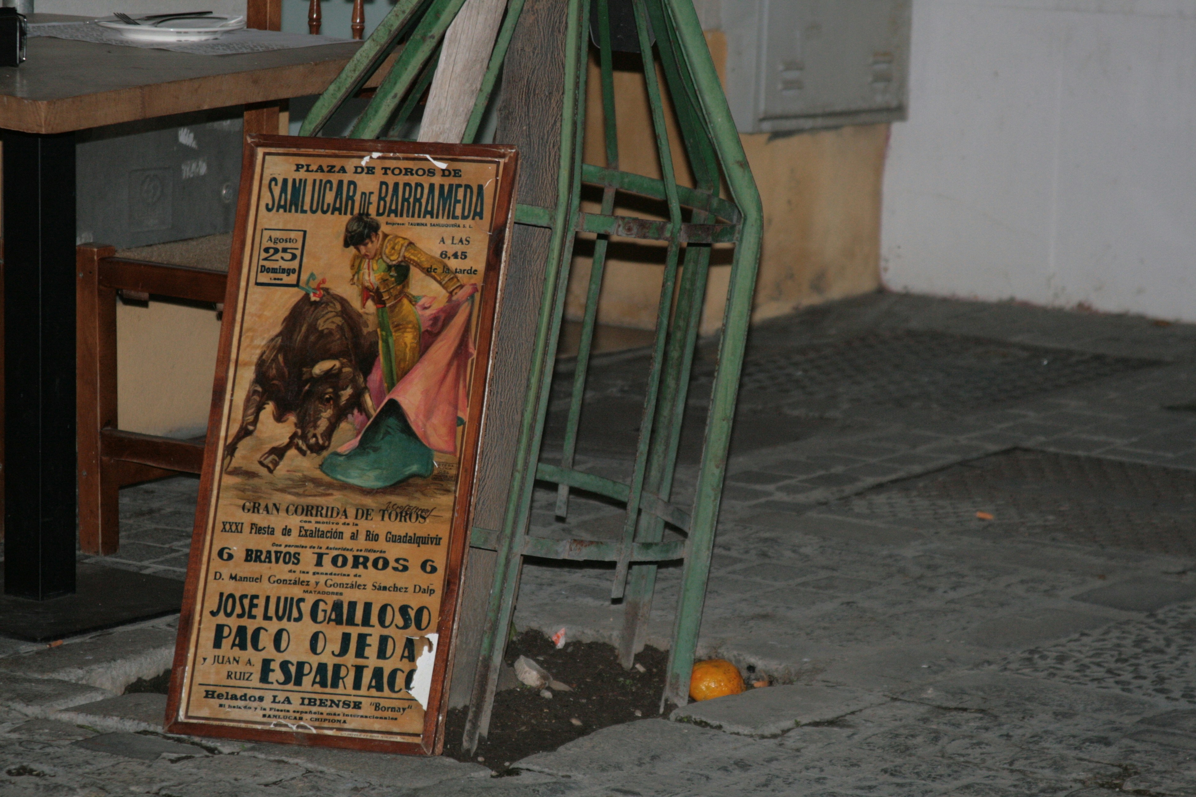 Vintage bullfighting poster propped against a green structure, showcasing cultural heritage with a hint of urban decay.