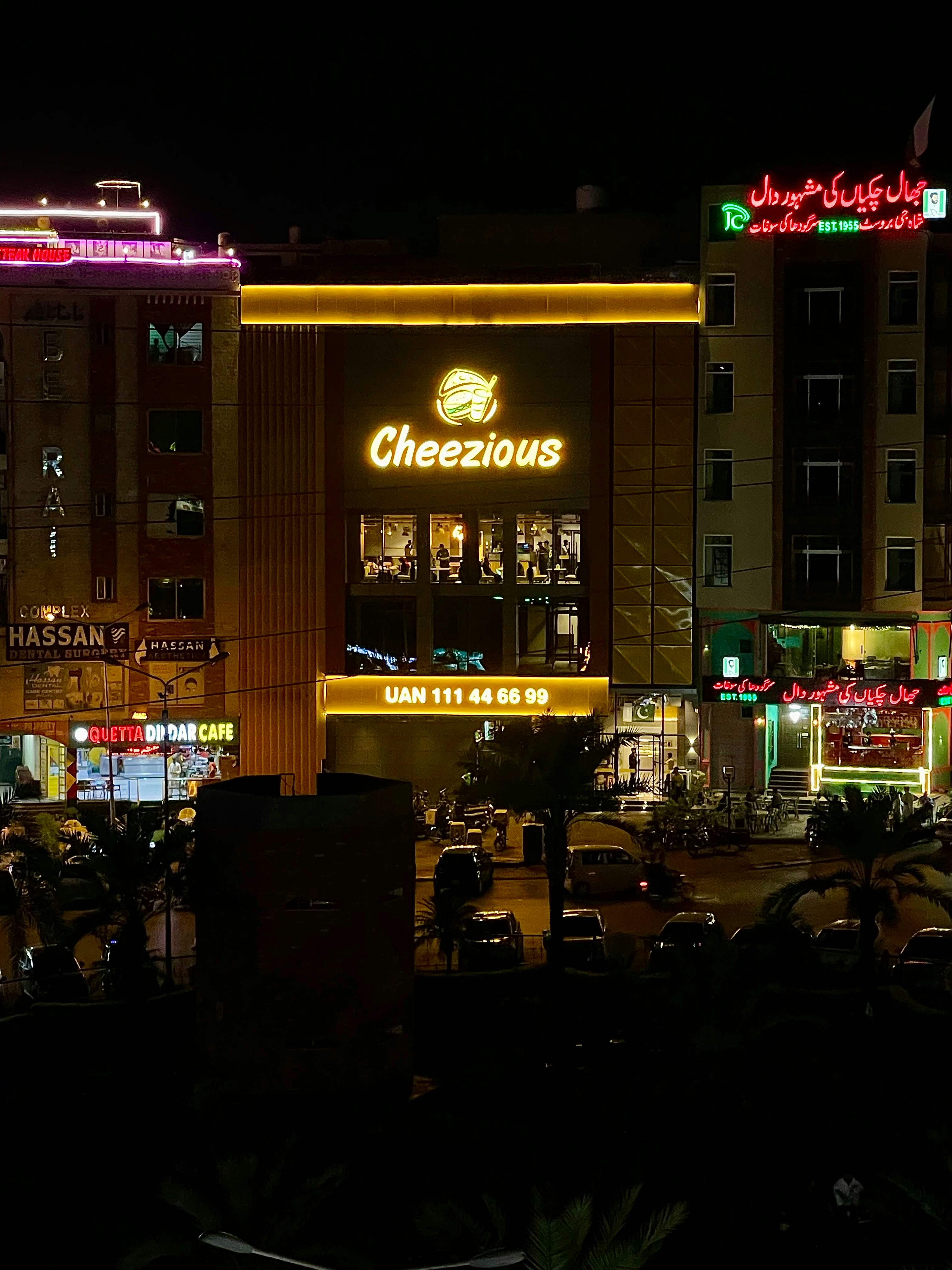 Cheezious Dark Wallpaper | Modern building with illuminated "cheezious" sign at night.