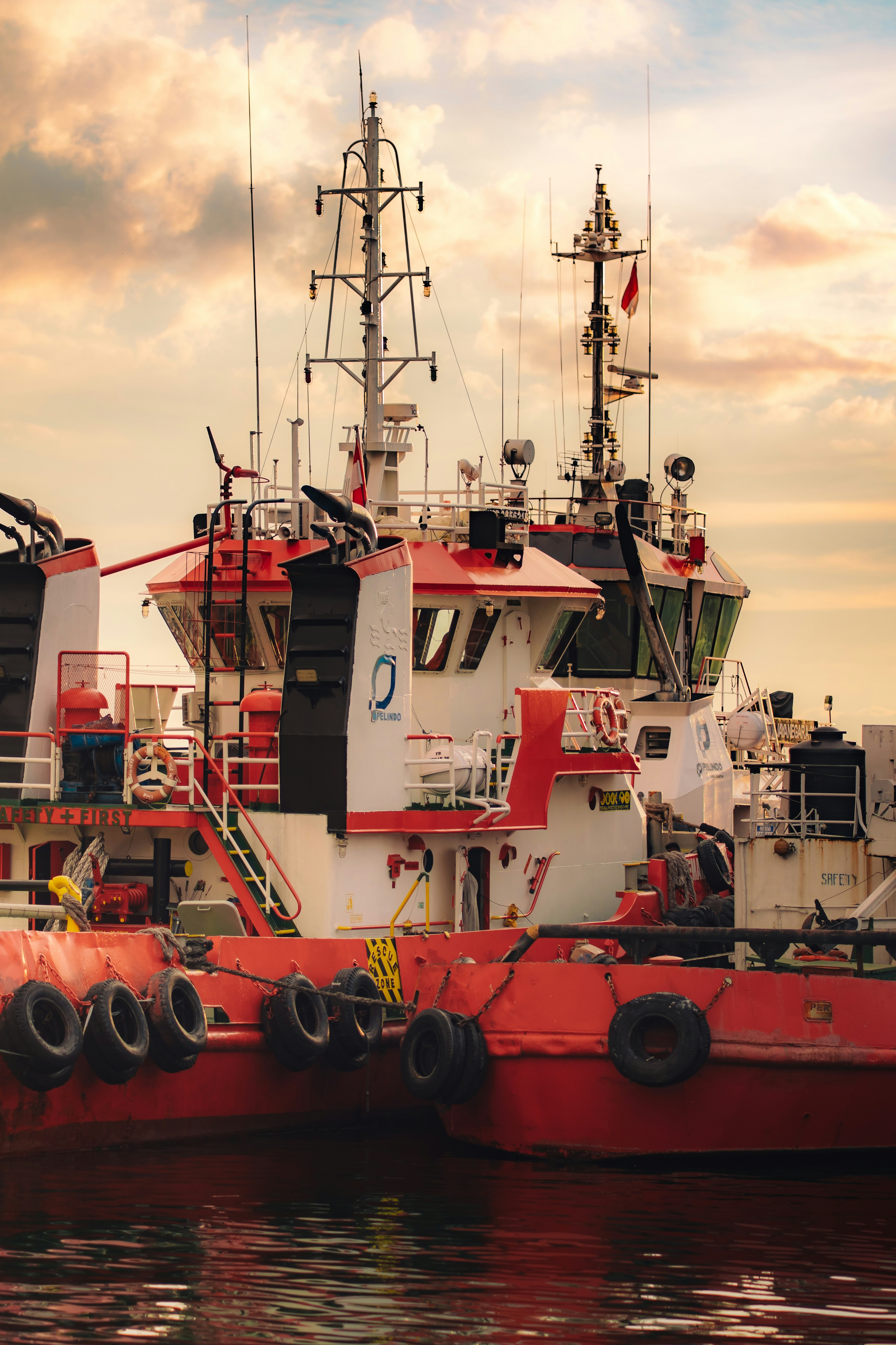 Two red tugboats docked at a harbor