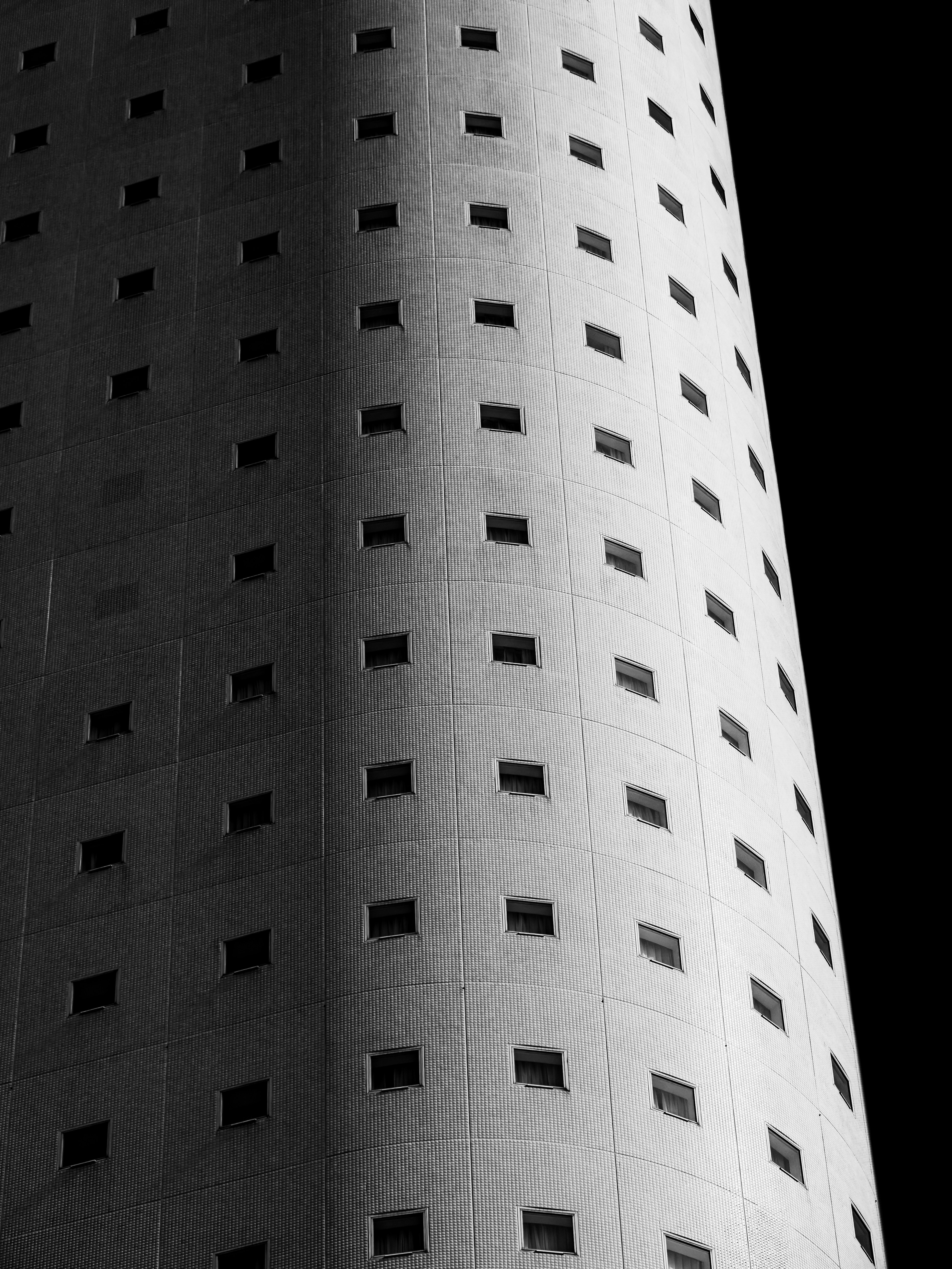 Monochrome Facade: A Tiled Tower Recedes into Darkness