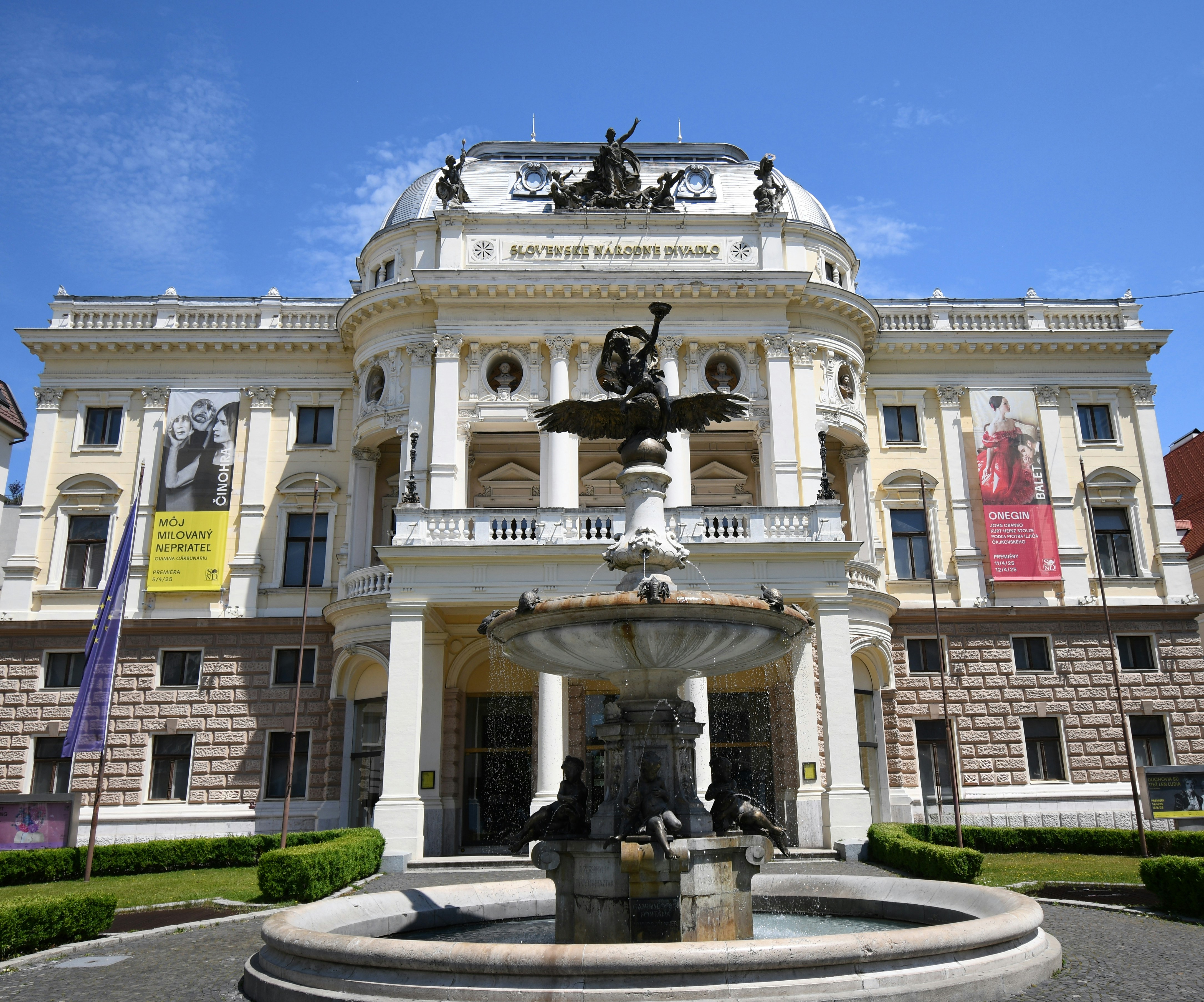 Ornate building with fountain and banners under blue sky
