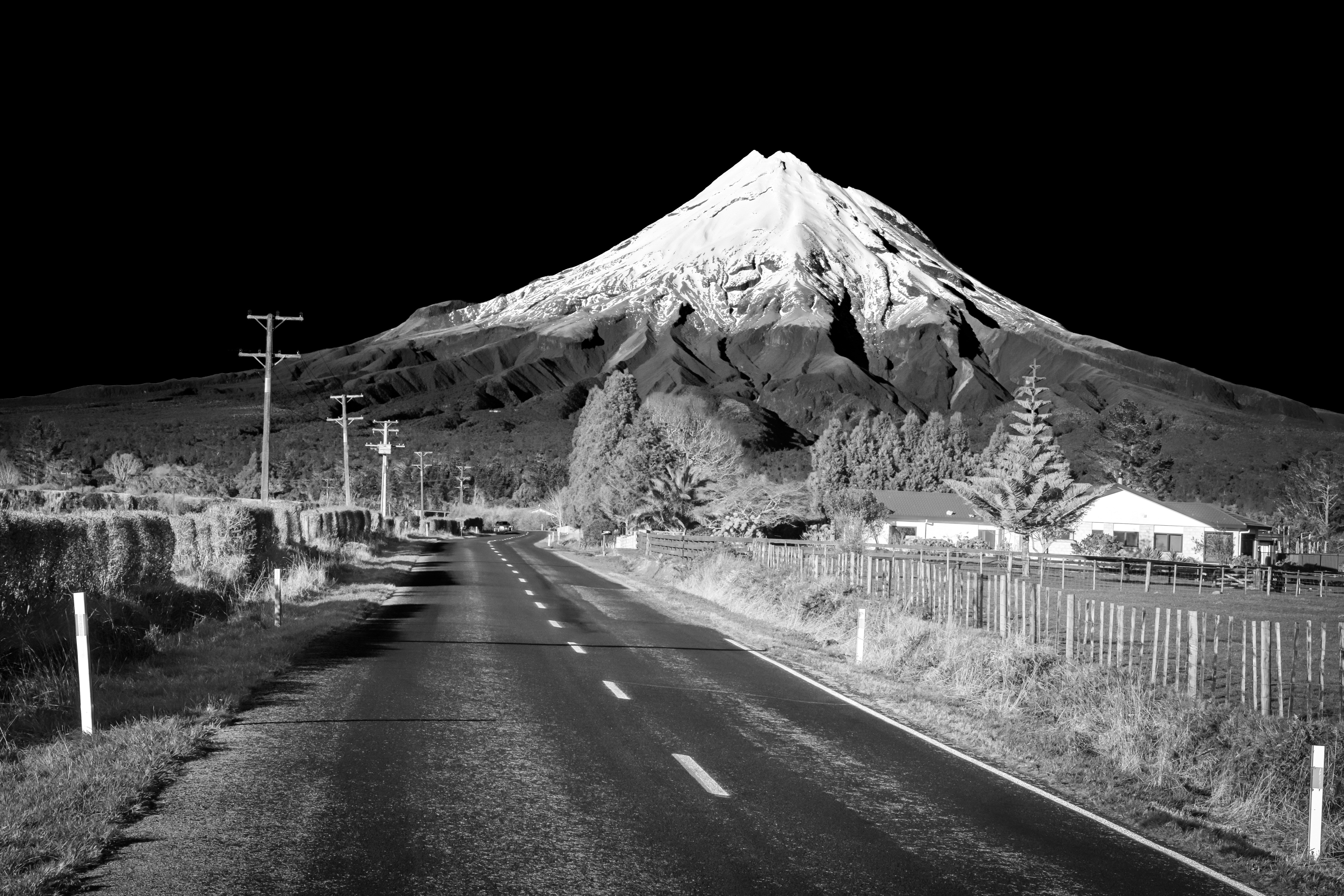 A perfectly formed, snow-capped volcano | Snow-capped mountain peak beside a road