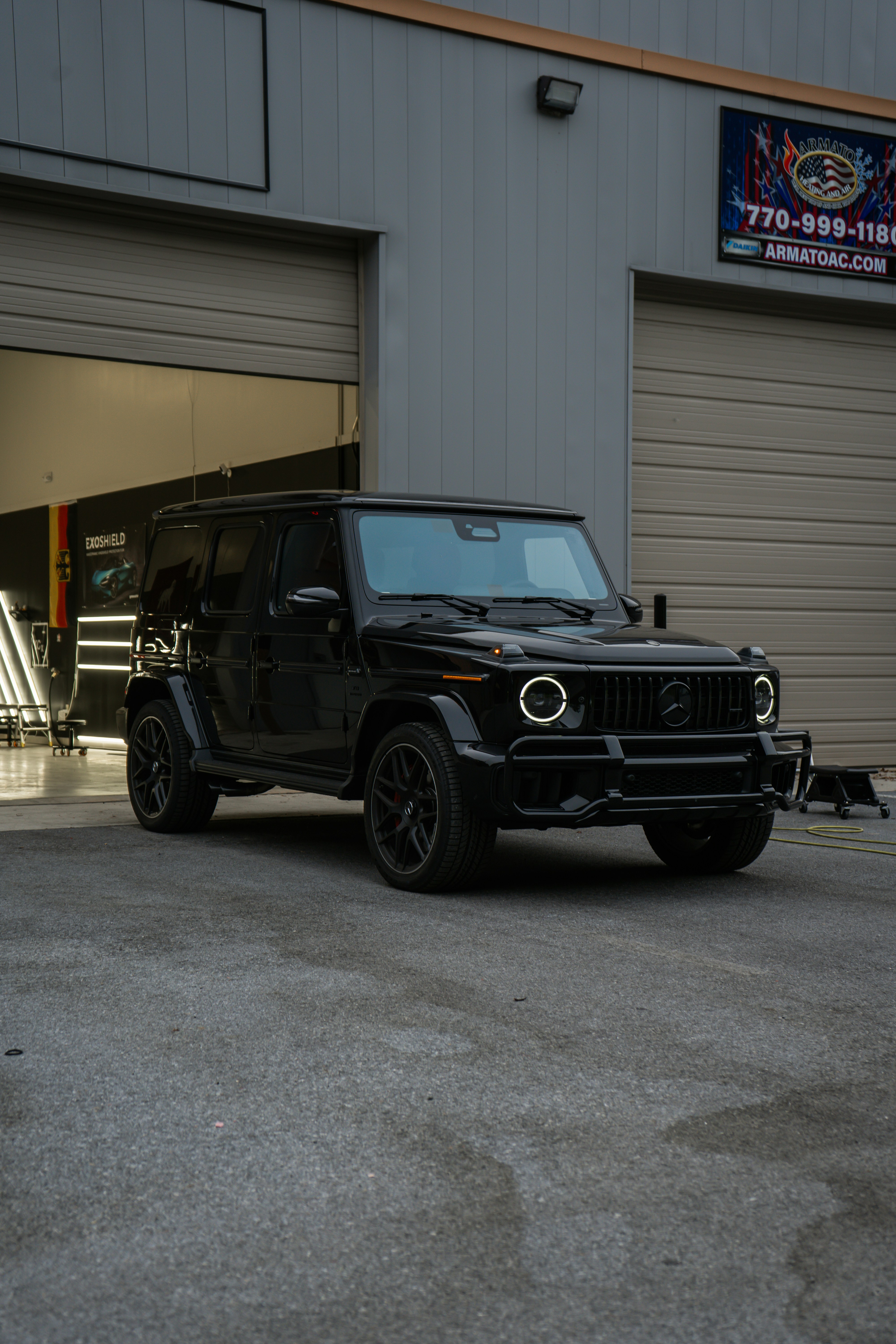 A sleek black SUV positioned in front of a garage, showcasing its bold design and modern features.