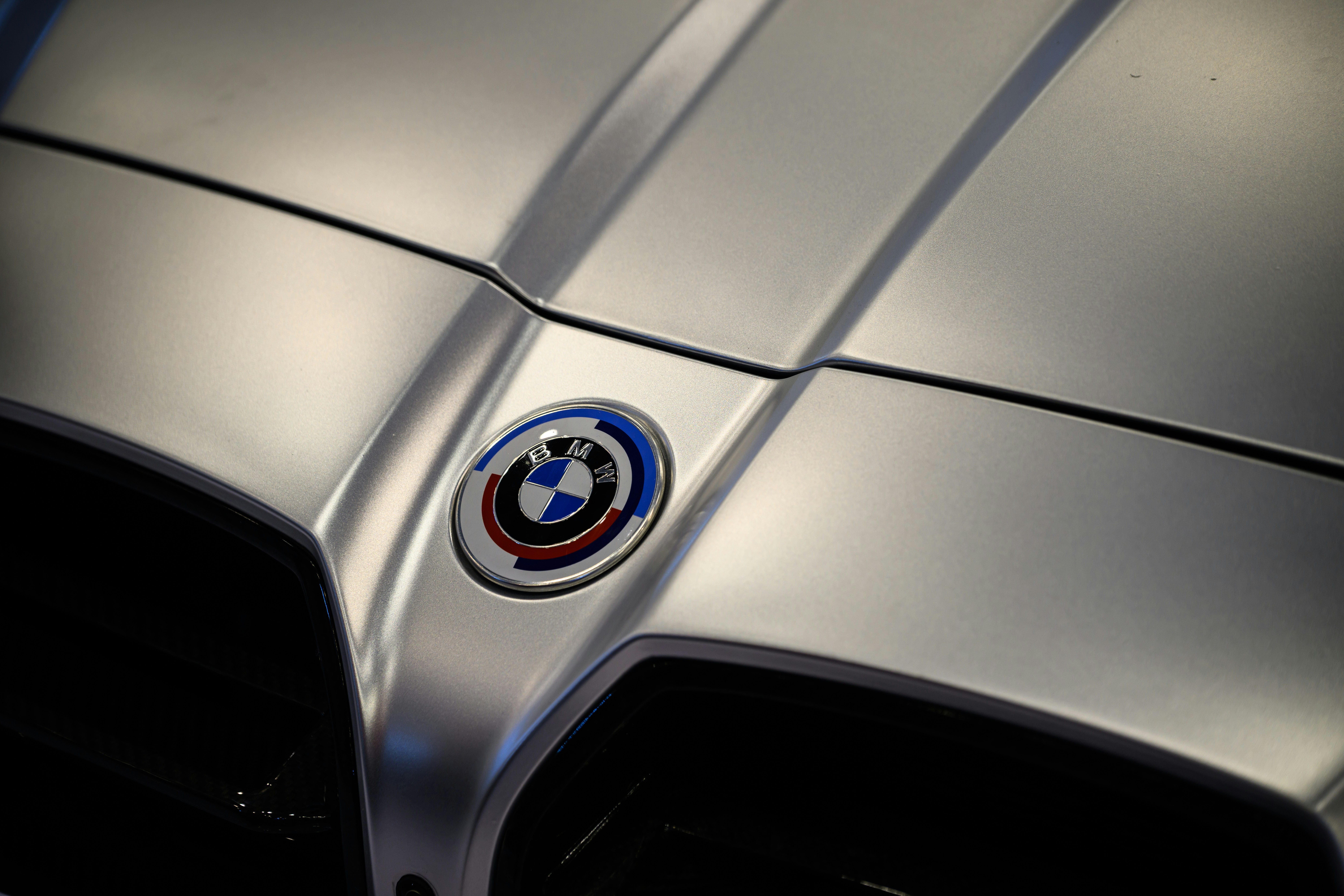 Close-up of a BMW logo on a sleek silver car hood, showcasing the brand's commitment to quality and design.