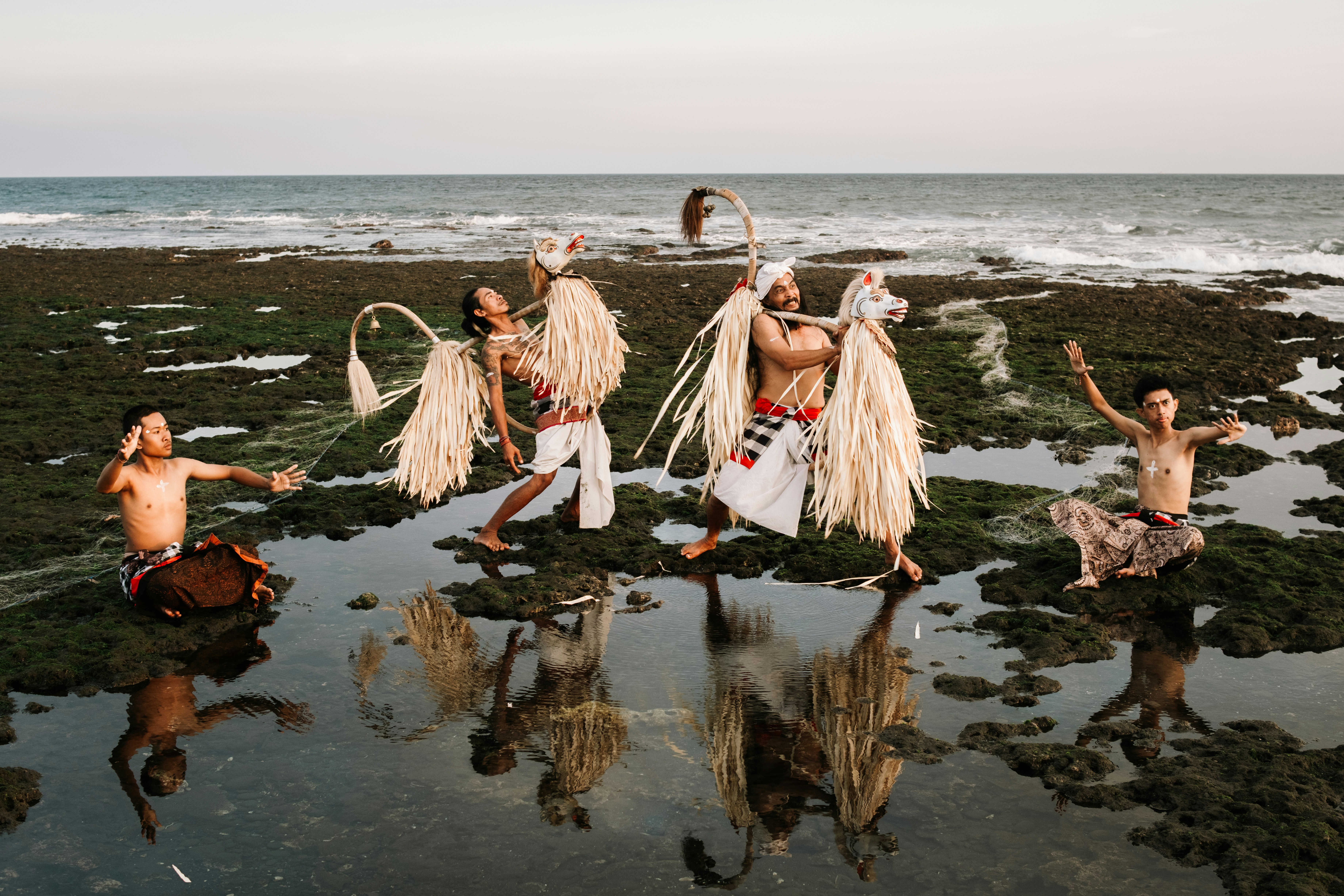 Tidal Echoes: Grass-Skirt Dancers on a Rocky Shore at Dusk