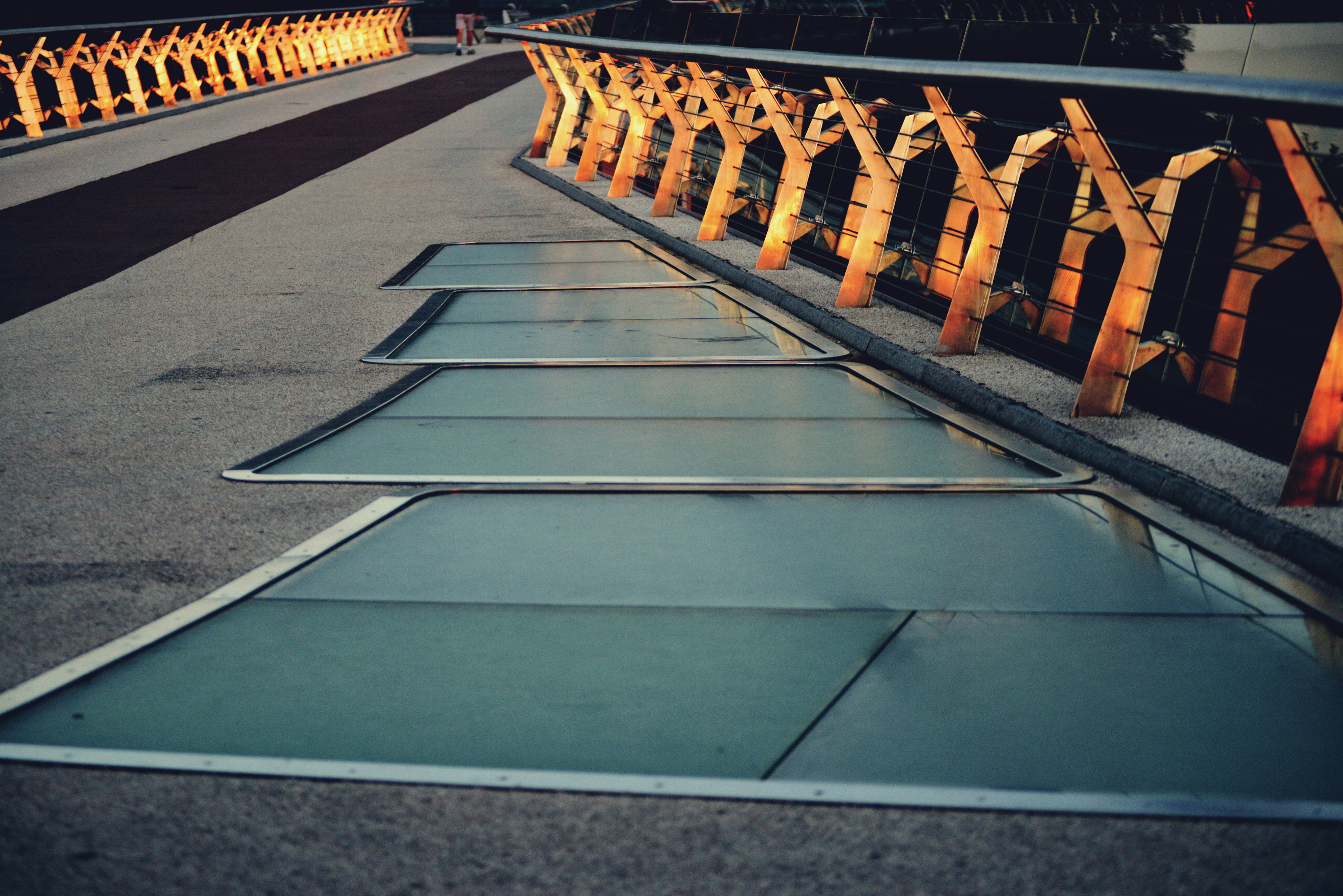 Modern bridge walkway with glass panels and railing.