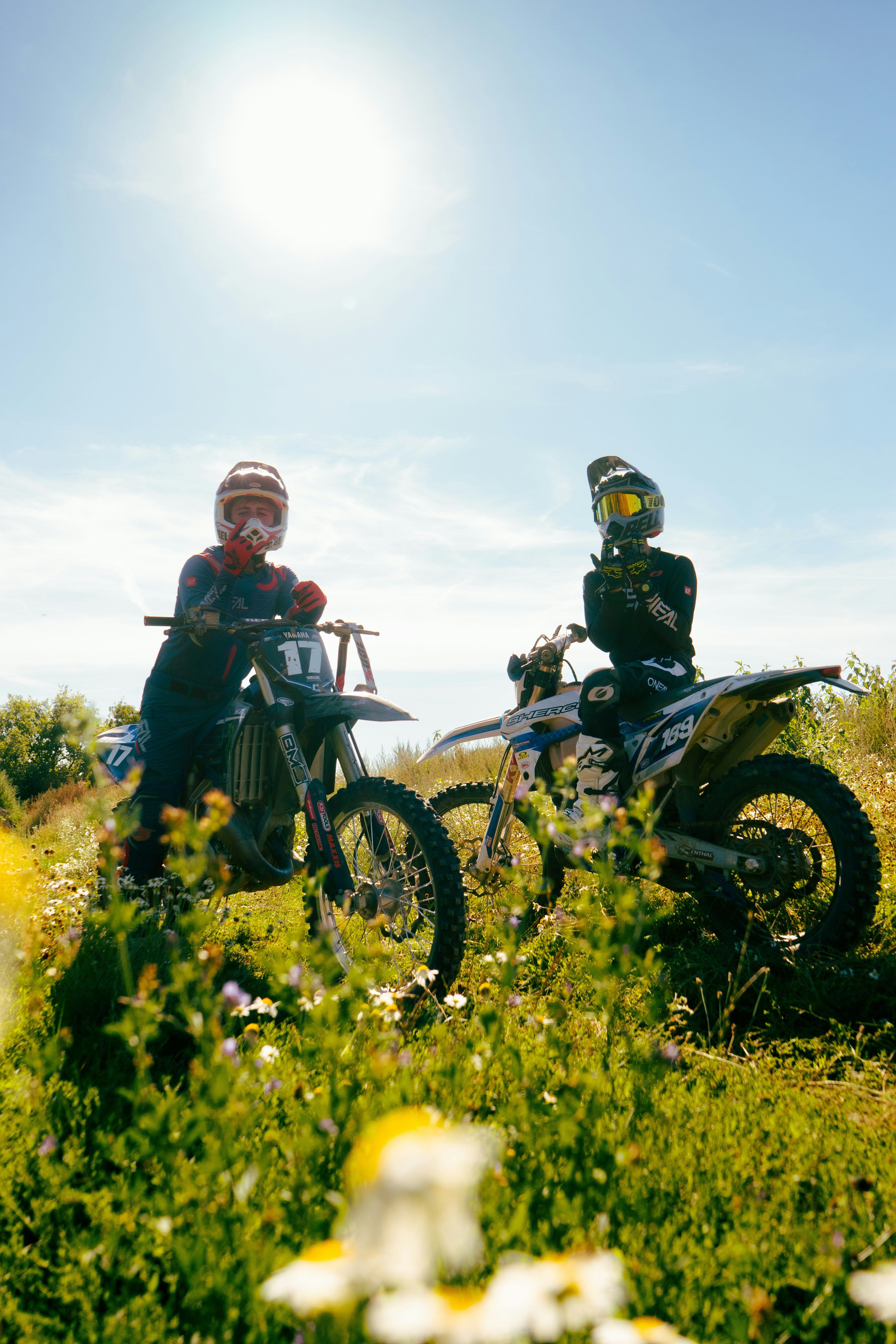 Throttle and Quiet: Two Dirt-Bike Riders Halt in a Sunlit Meadow