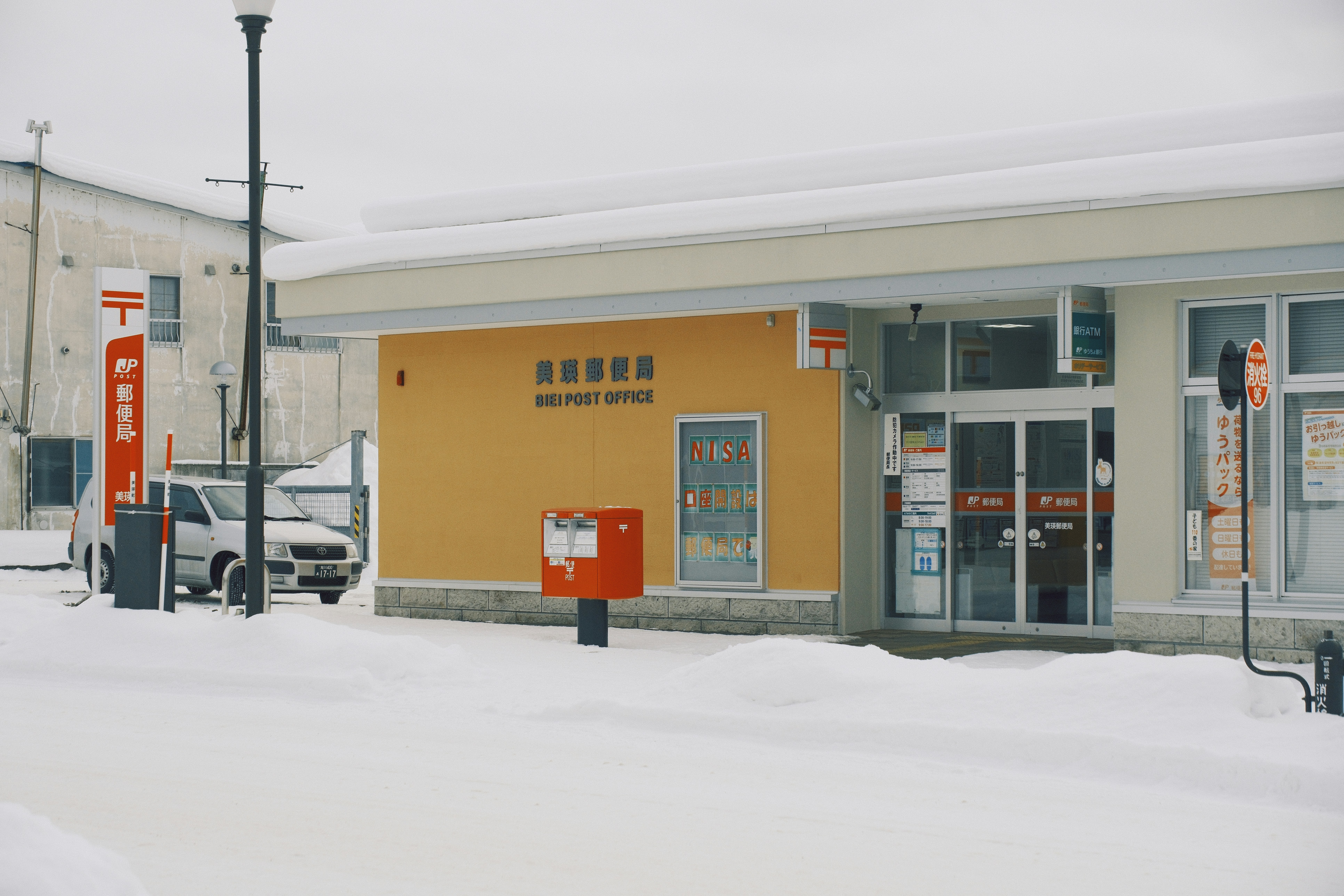 A quaint post office nestled in a snowy landscape, showcasing bright orange and white architecture against the winter backdrop.
