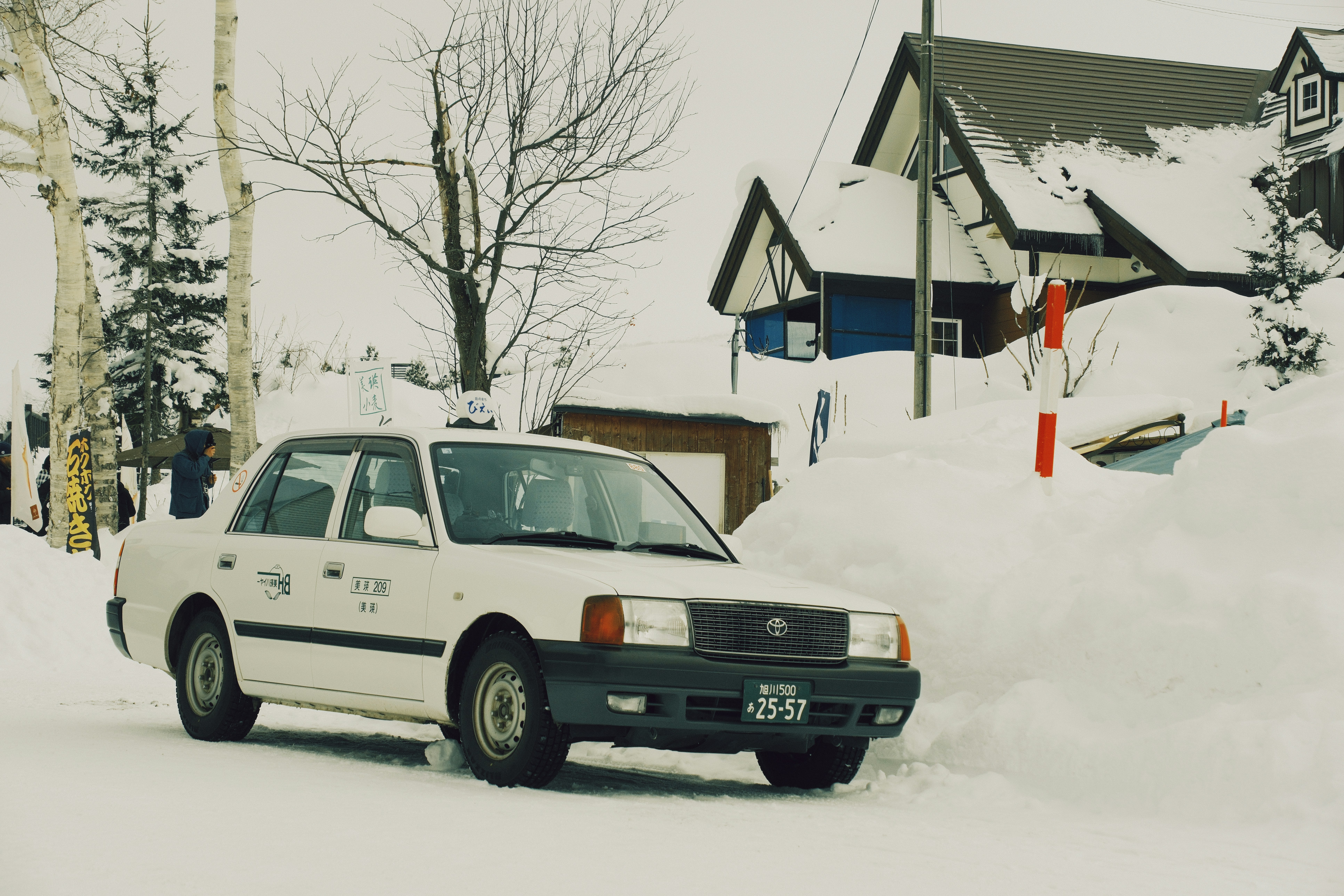 White taxi parked in snowy village with houses