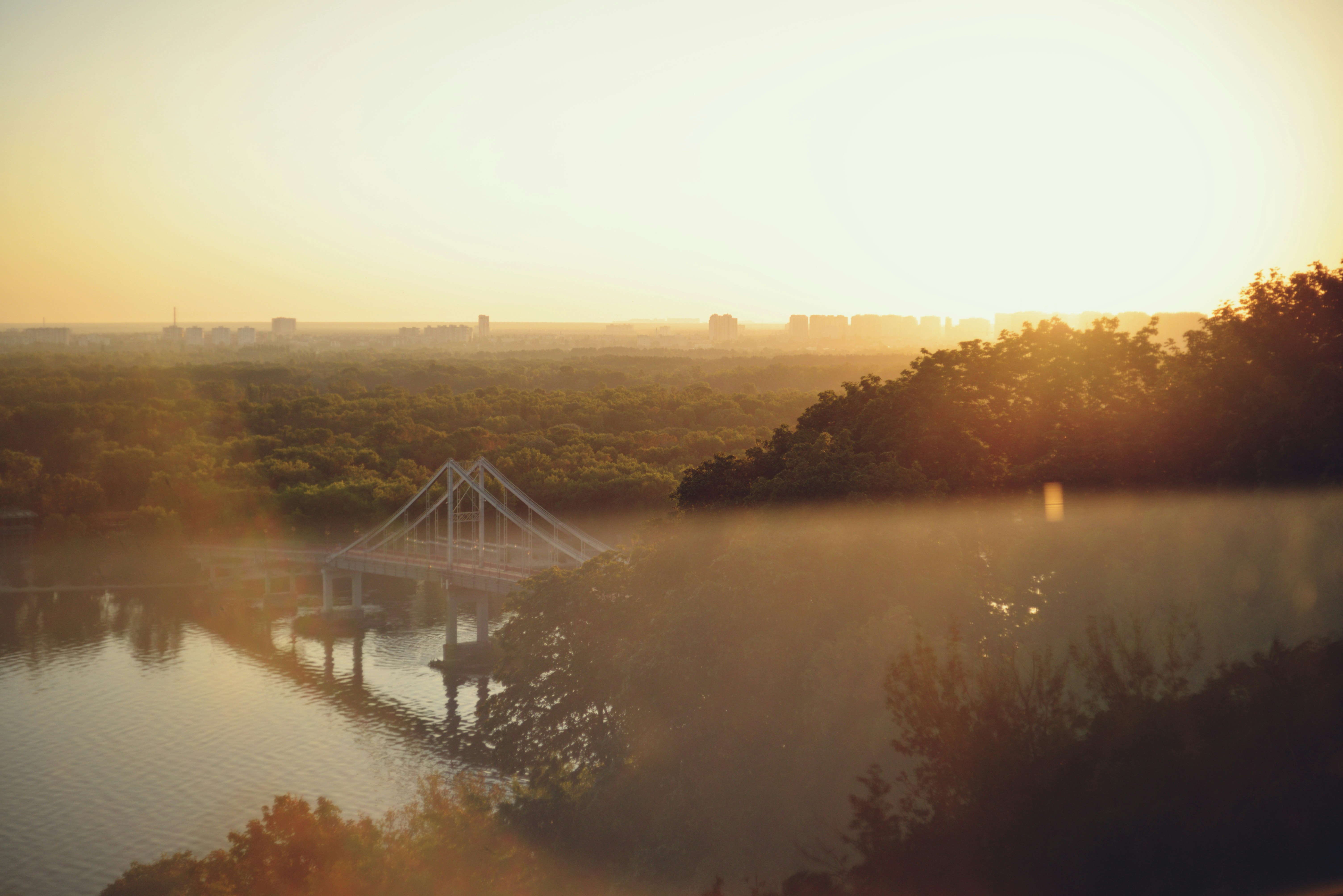 Sunrise over a misty river with a bridge.