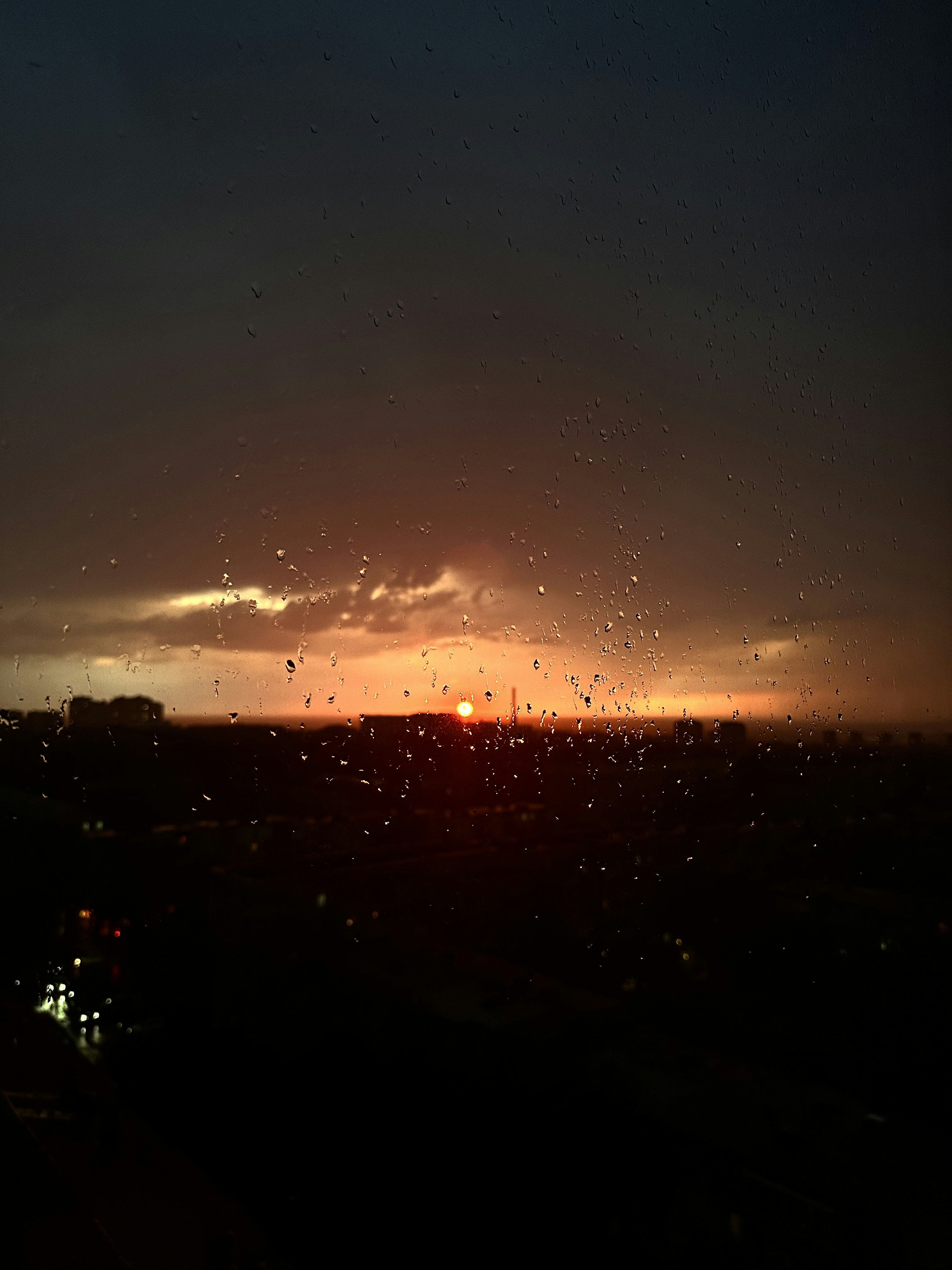 Sunset over a city seen through a rainy window.