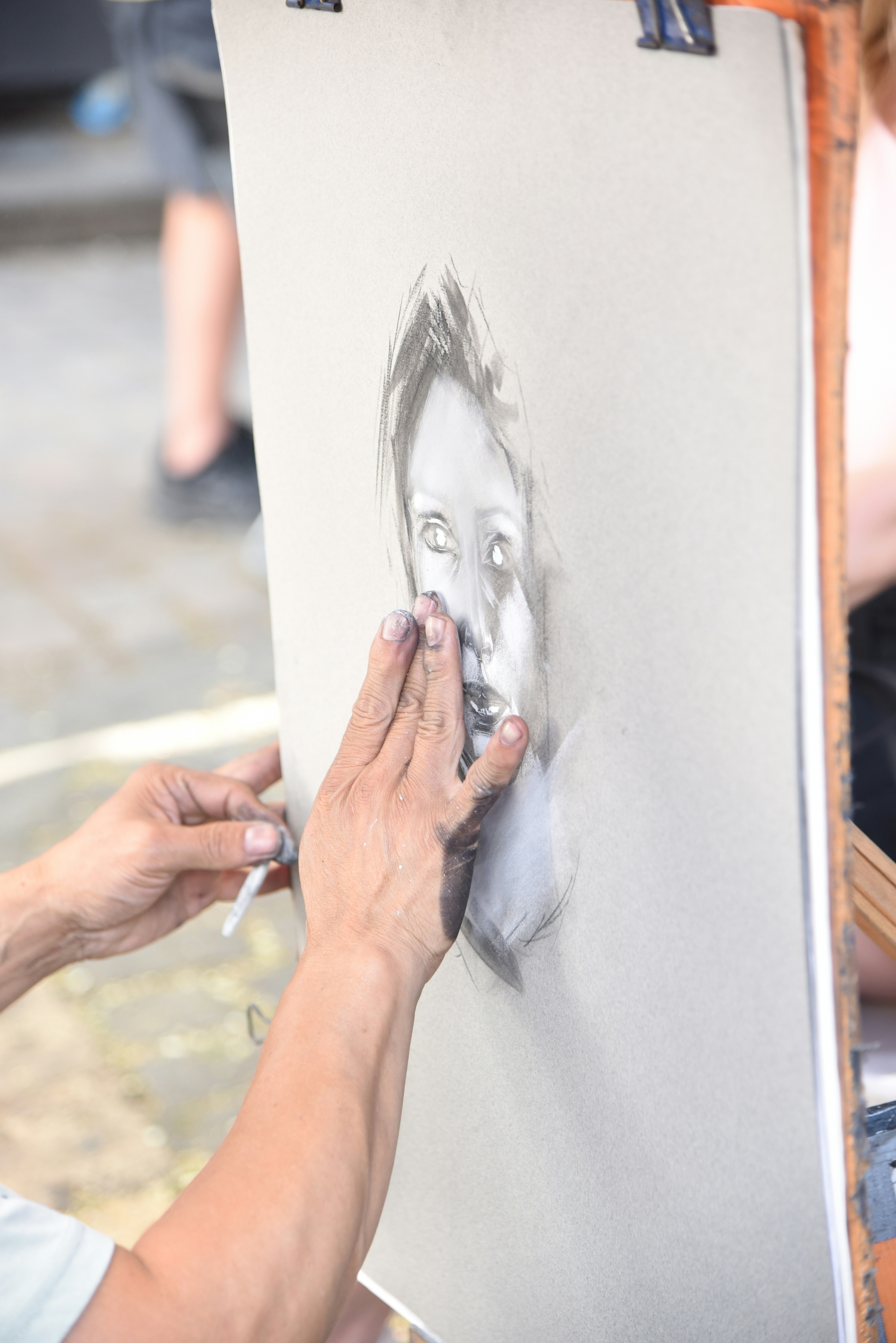 Artist drawing a portrait on paper with charcoal.