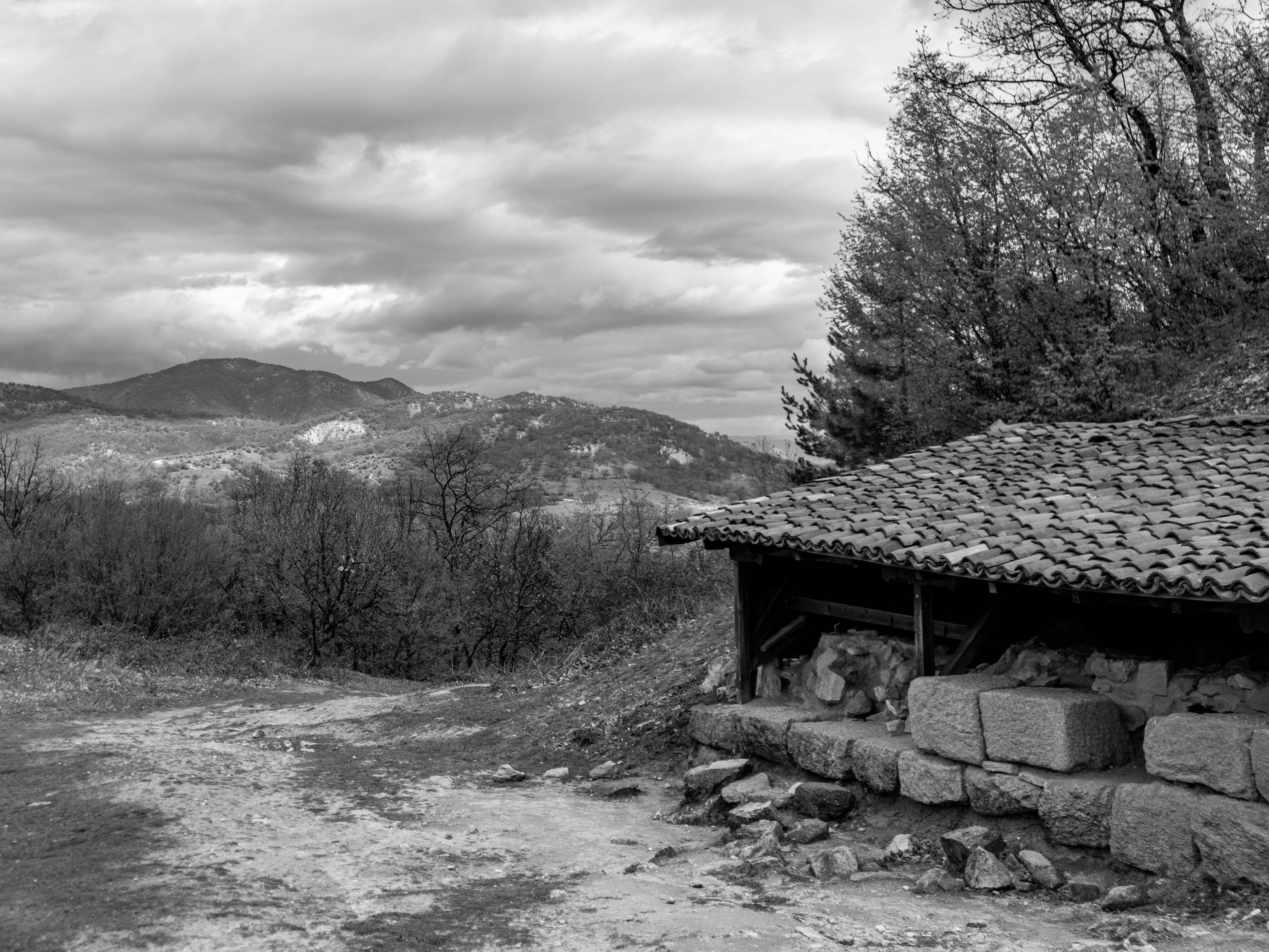 Weathered stone structure nestled in a rugged landscape, framed by dark clouds and distant mountains. A testament to bygone times.