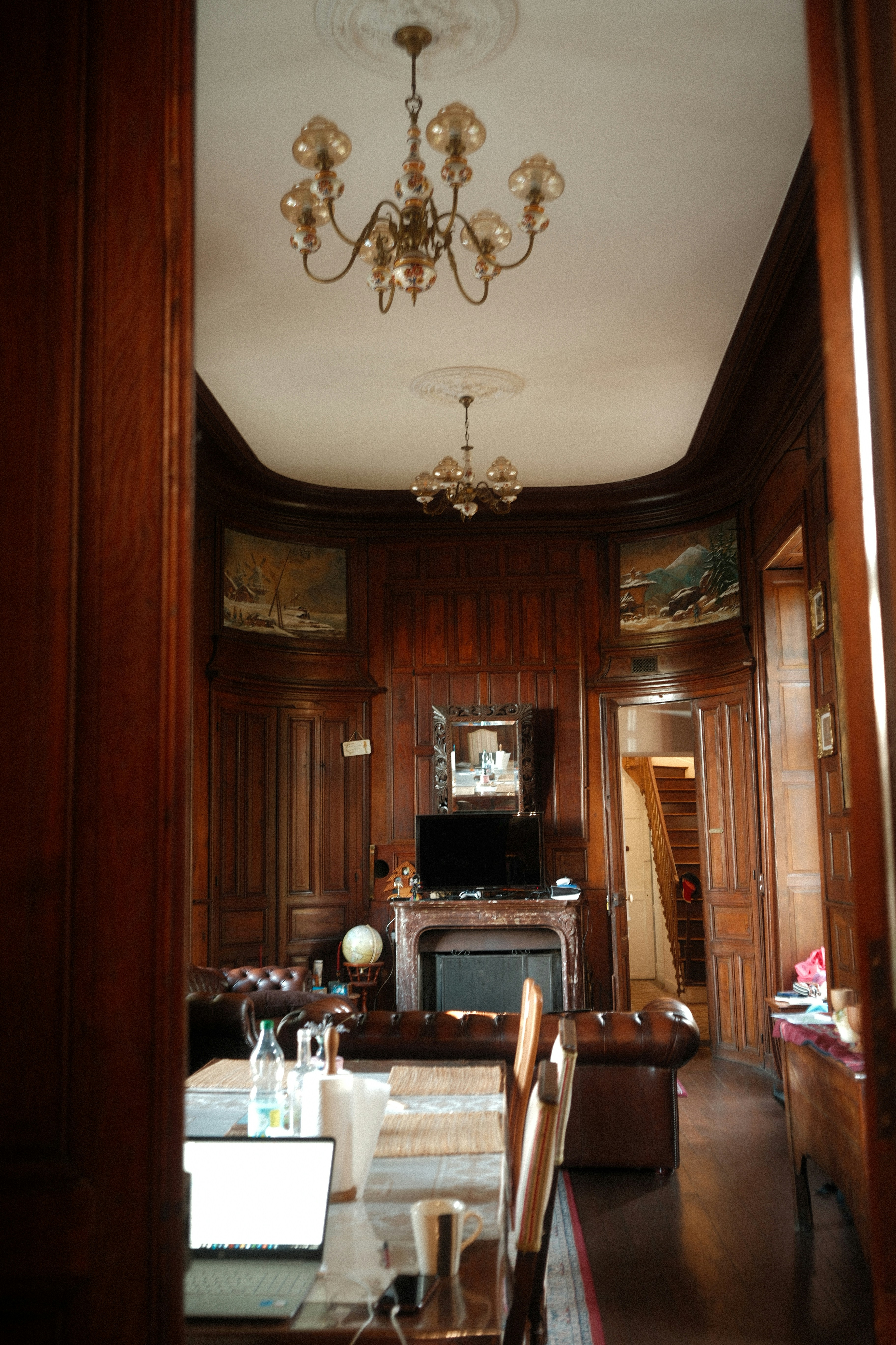 Luxurious wood-paneled room with antique furniture and chandeliers.