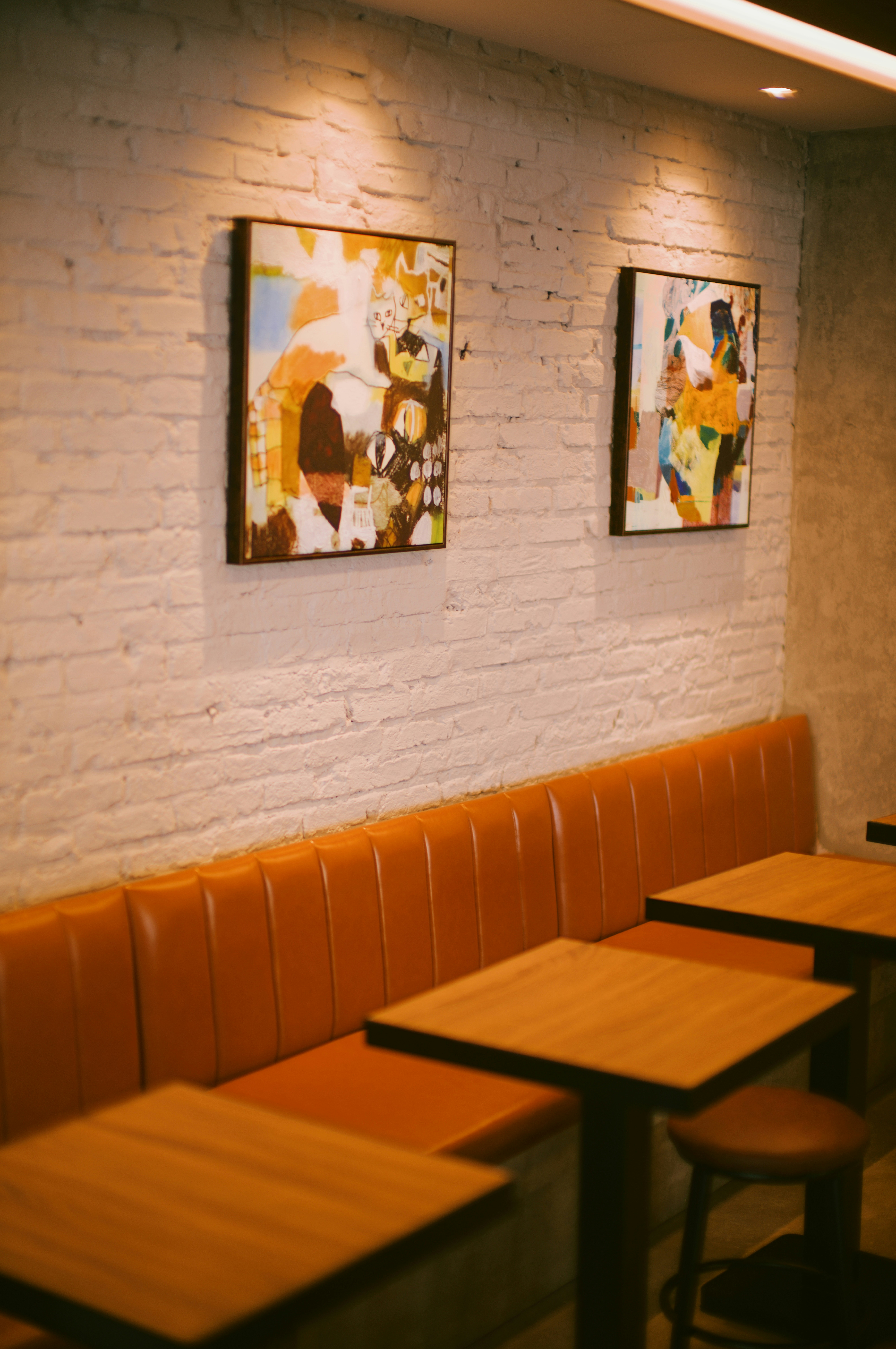 Modern dining area with orange booth seating and abstract art. photo ...