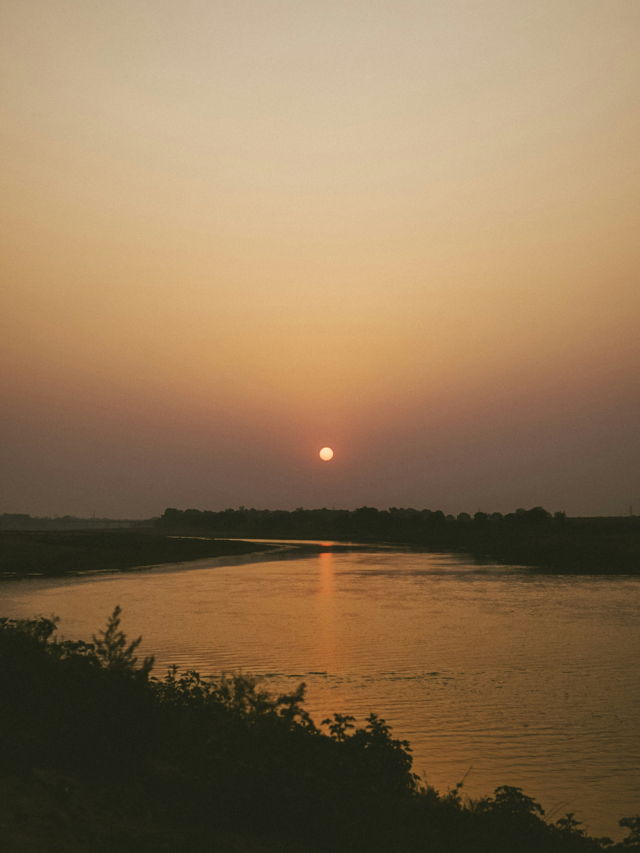 Sunset over a calm river with distant trees