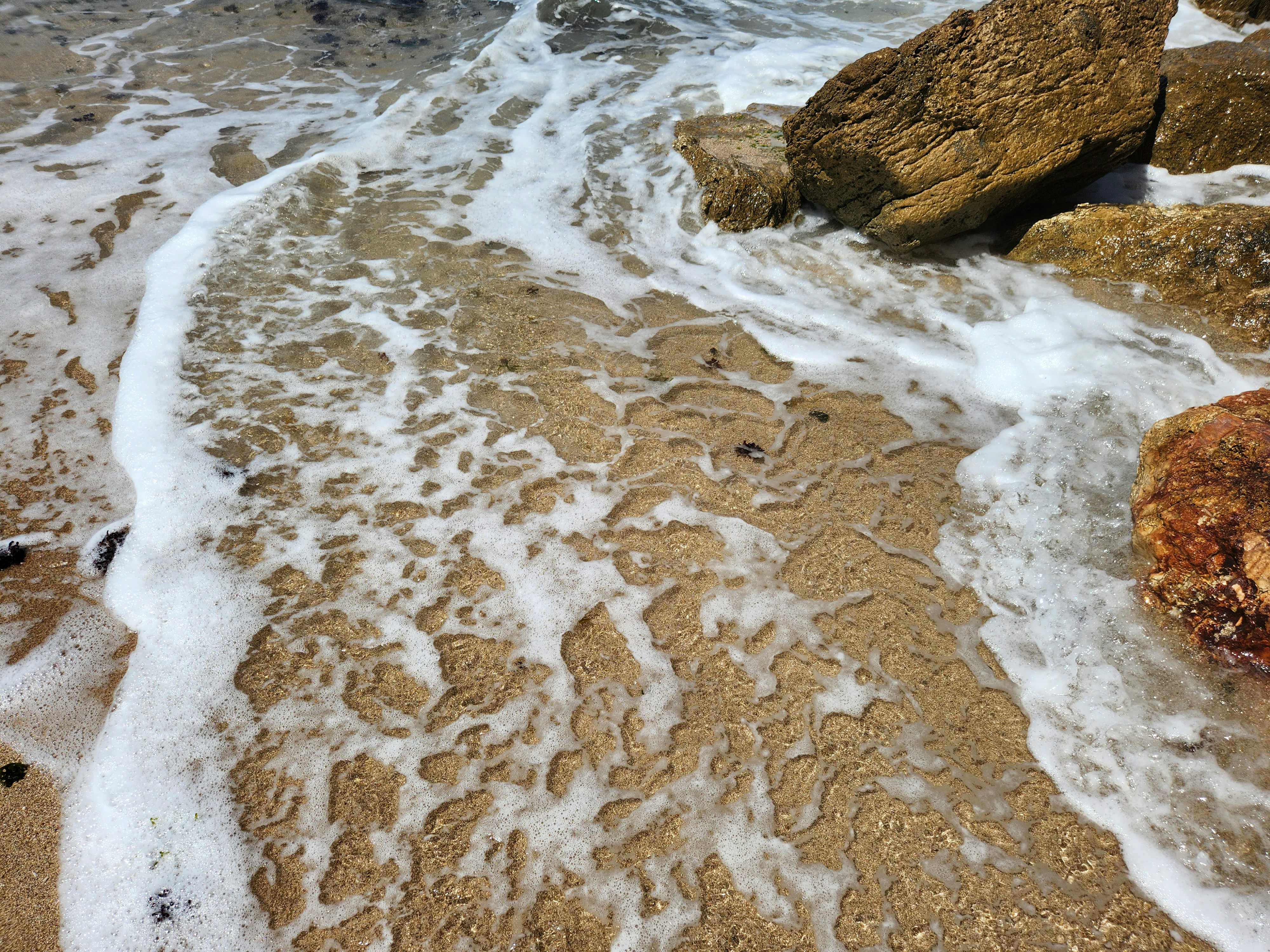 Waves Crashing on Sandy Shoreline with Rocks | Waves washing over sandy beach with rocks