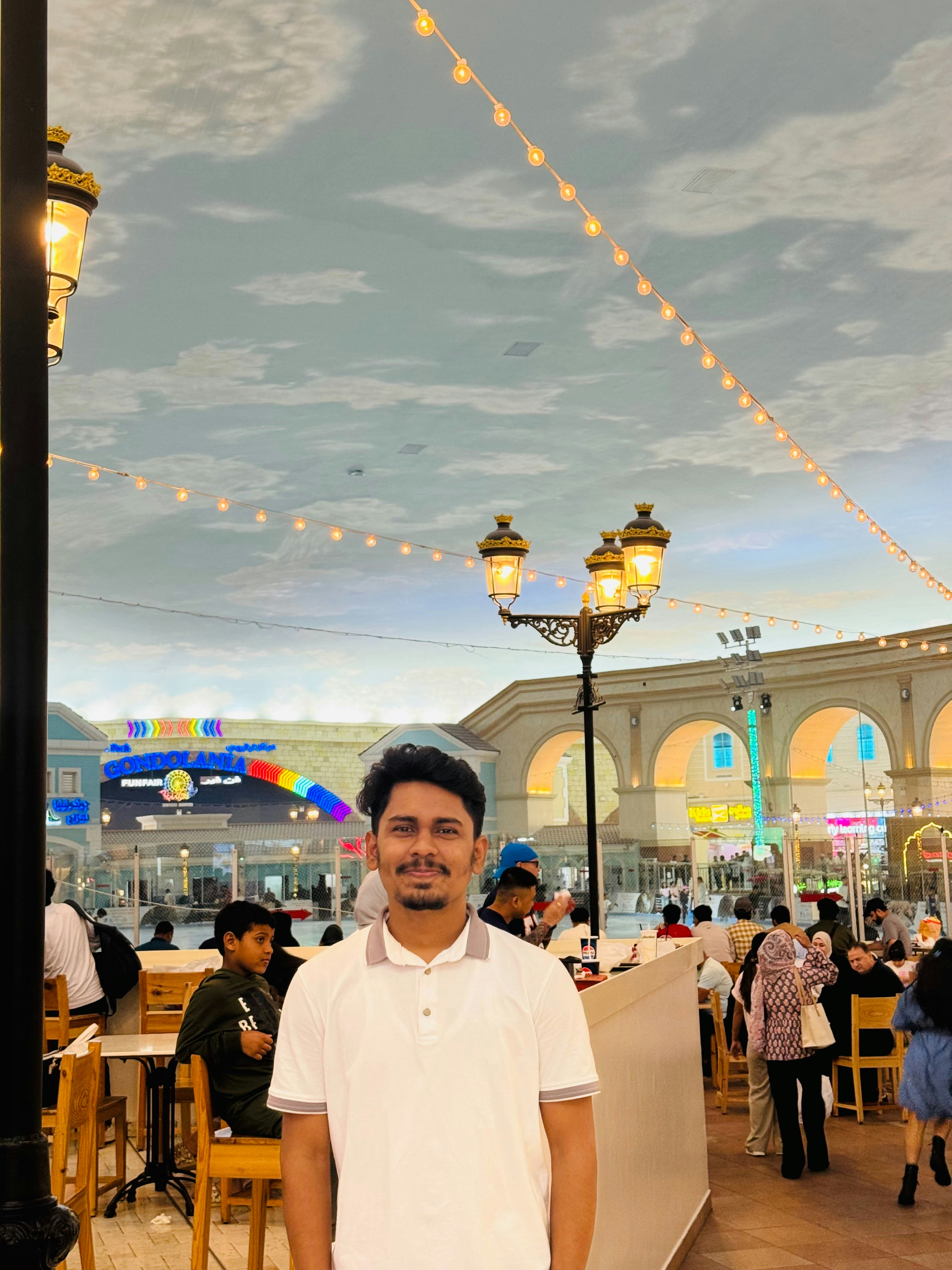Man standing in a brightly lit indoor shopping mall.
