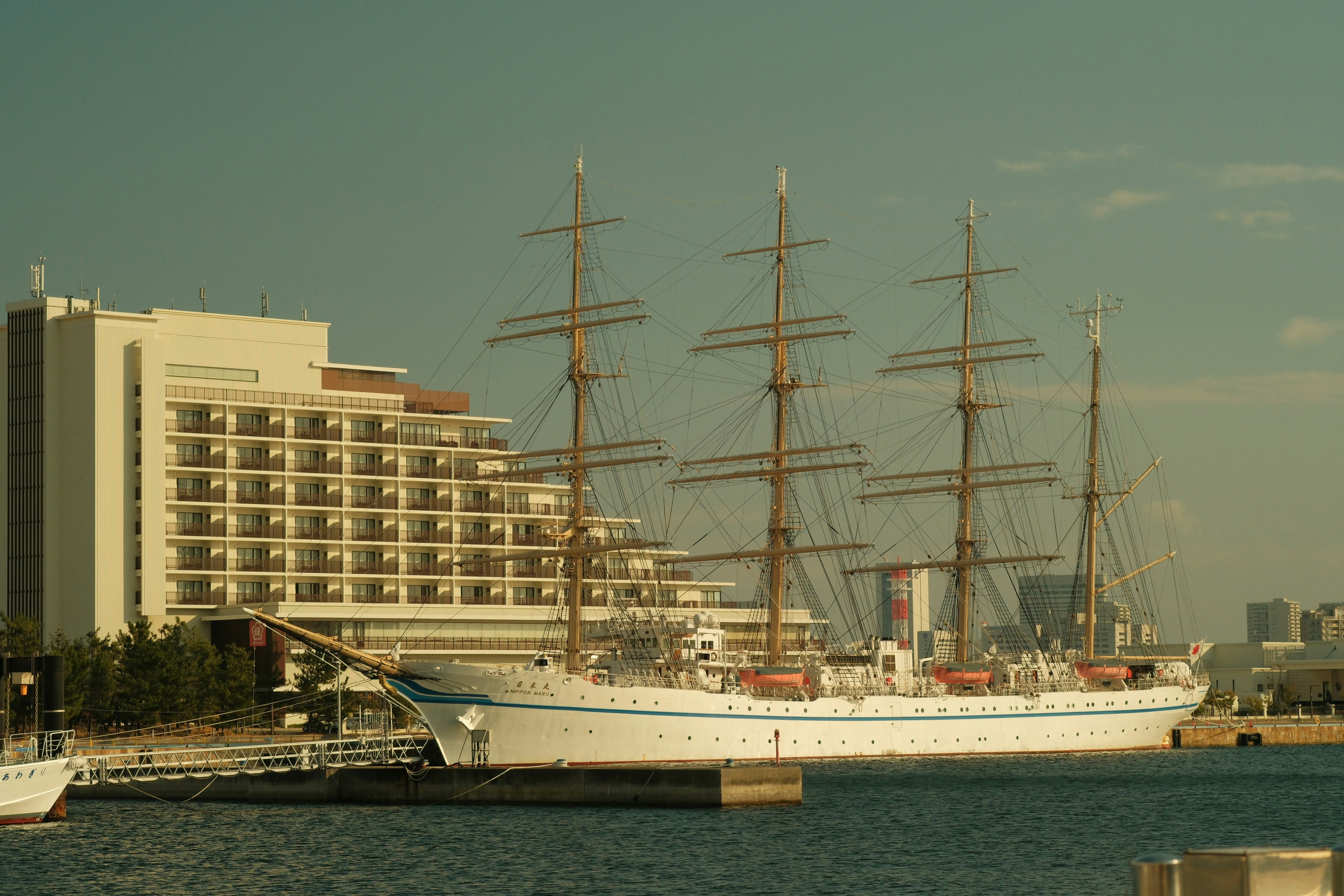 Historic tall ship docked beside a modern hotel, showcasing a blend of maritime heritage and contemporary architecture.