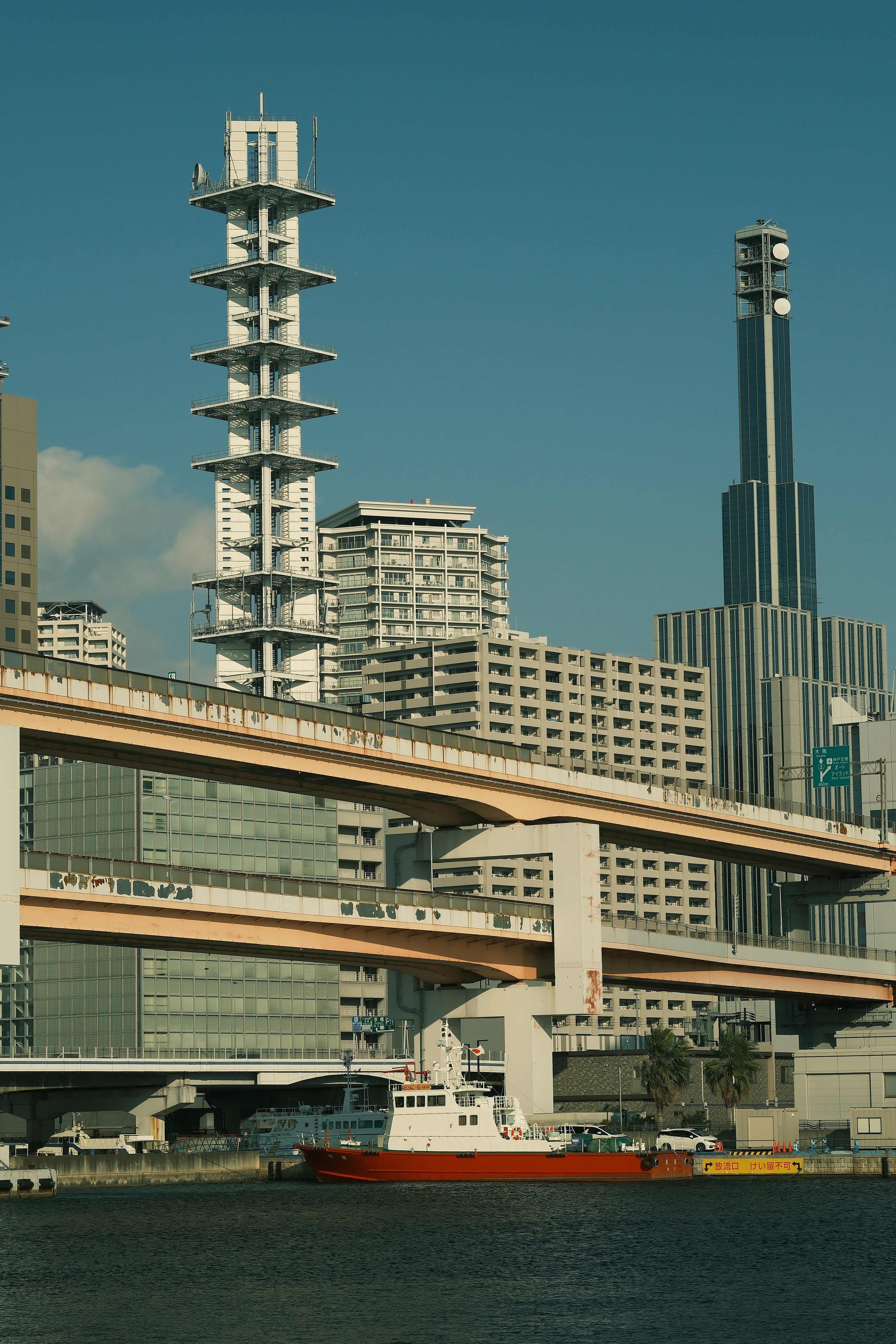 Modern cityscape with elevated highways and a boat.