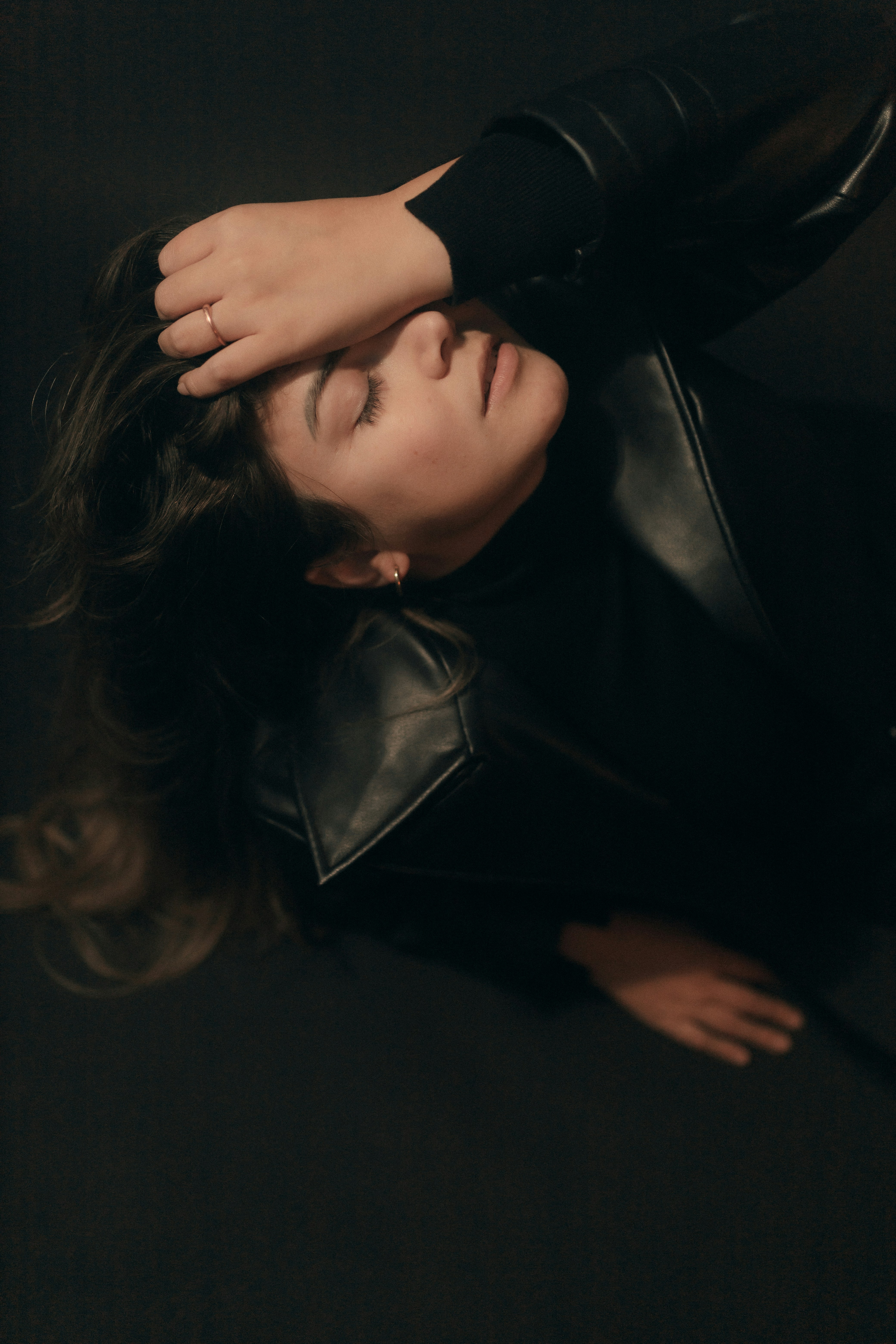 Woman in leather jacket with hand on forehead