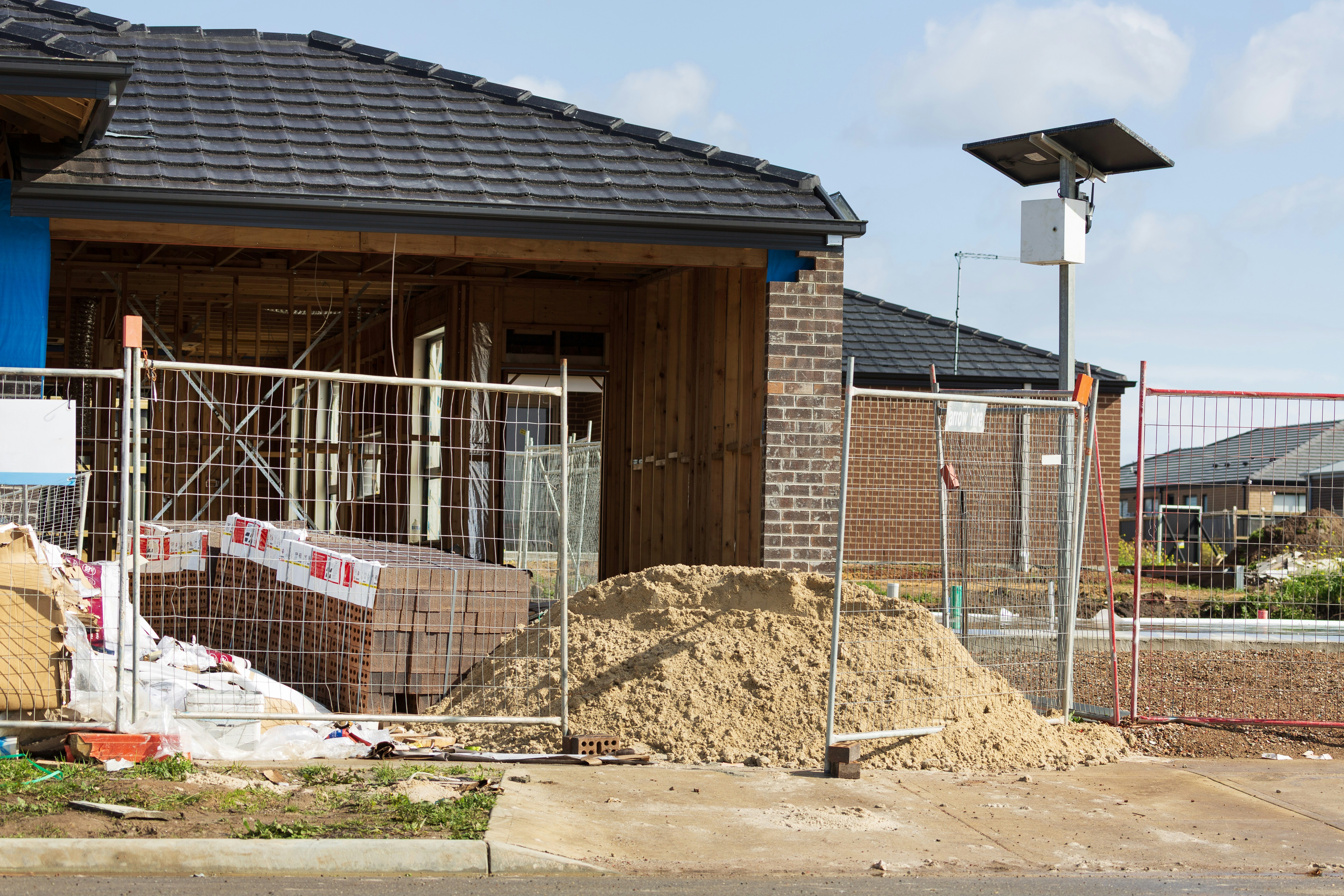 New home construction. | Construction site with building materials and fencing