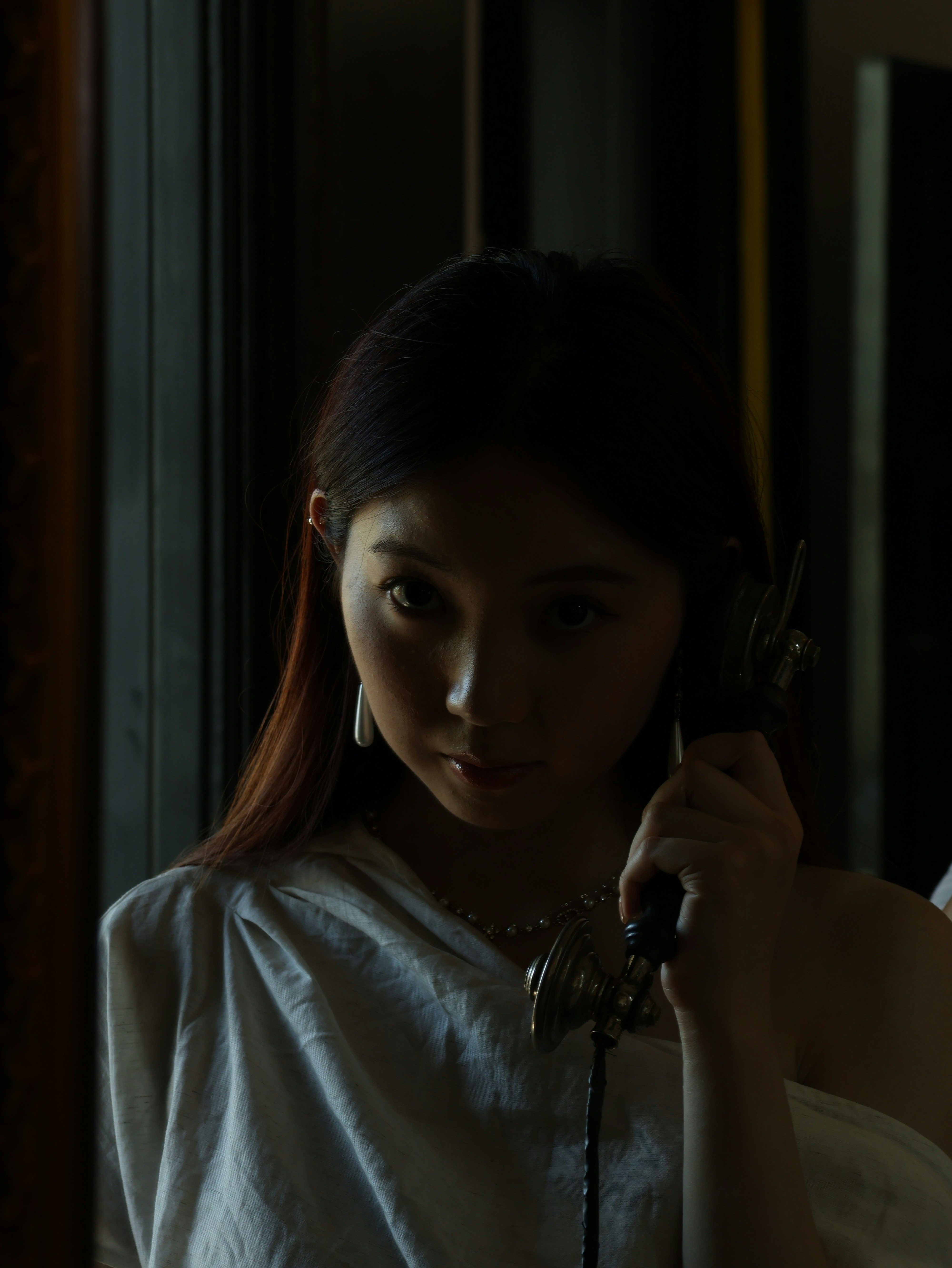 Don’t speak. | Woman holding an old telephone to her ear.