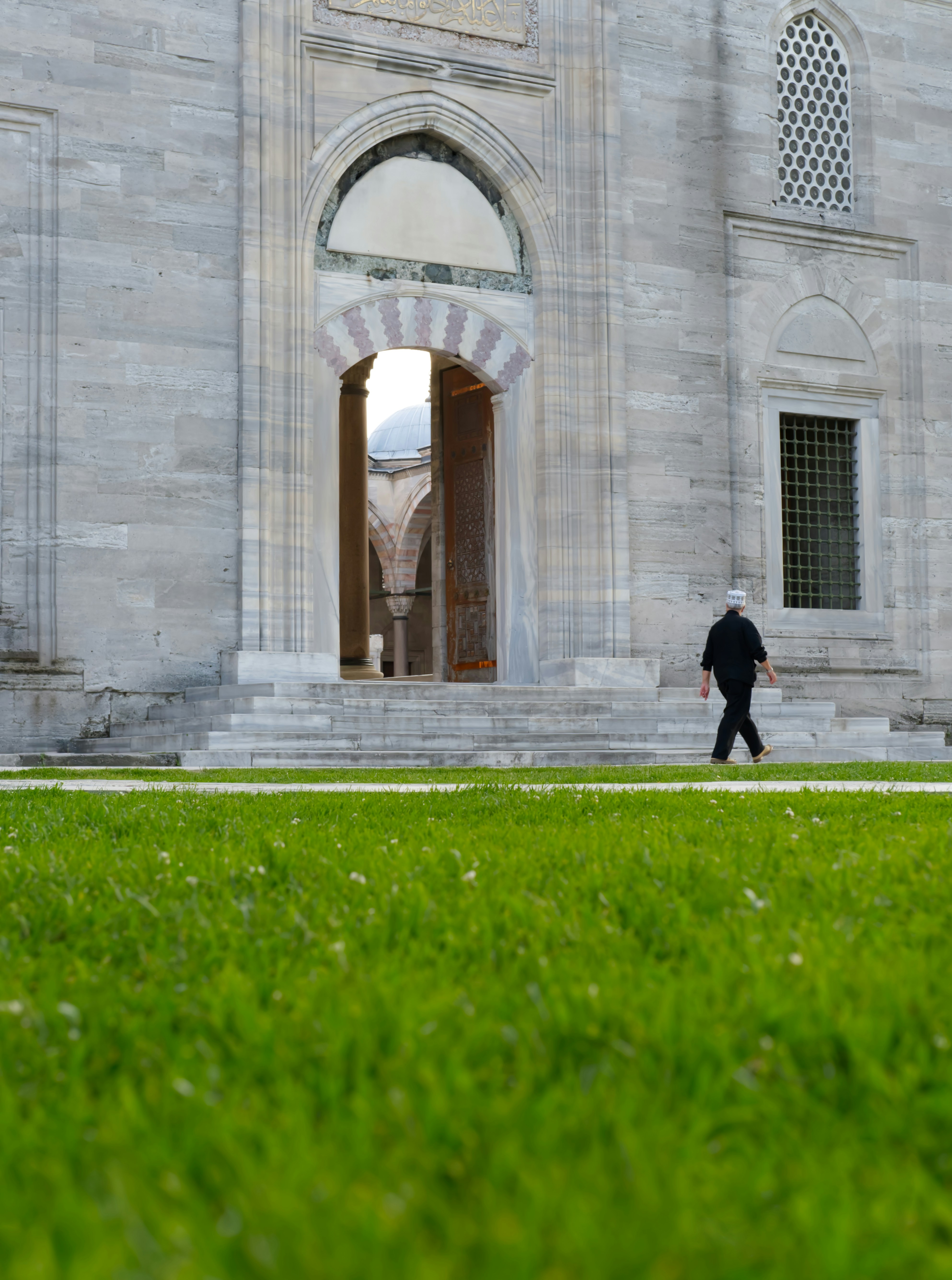 Man walks past a large stone building entrance.