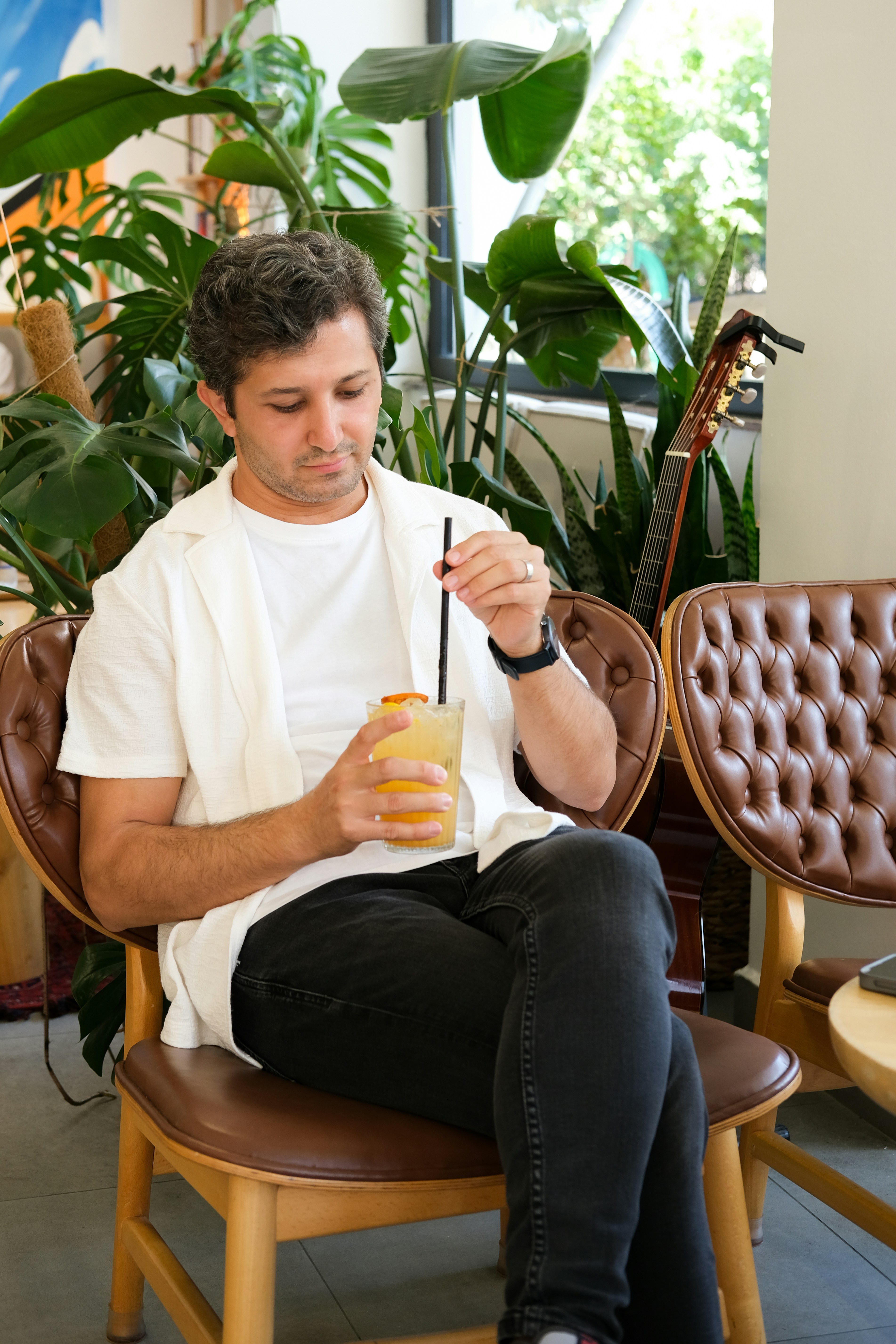 Man holding a drink with a straw and fruit.