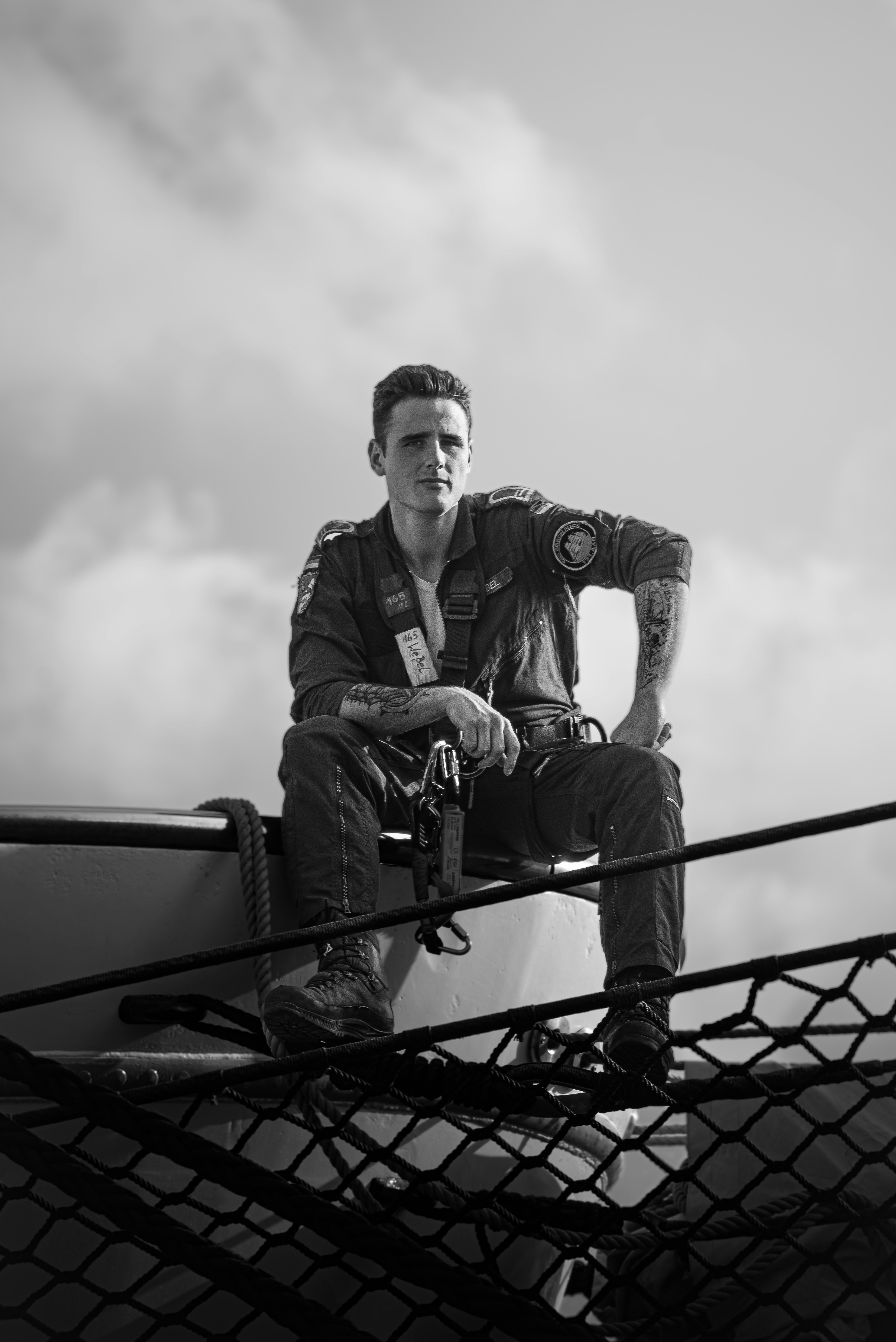 A determined aviator seated on a vessel, exuding confidence and readiness, captured in striking black and white.