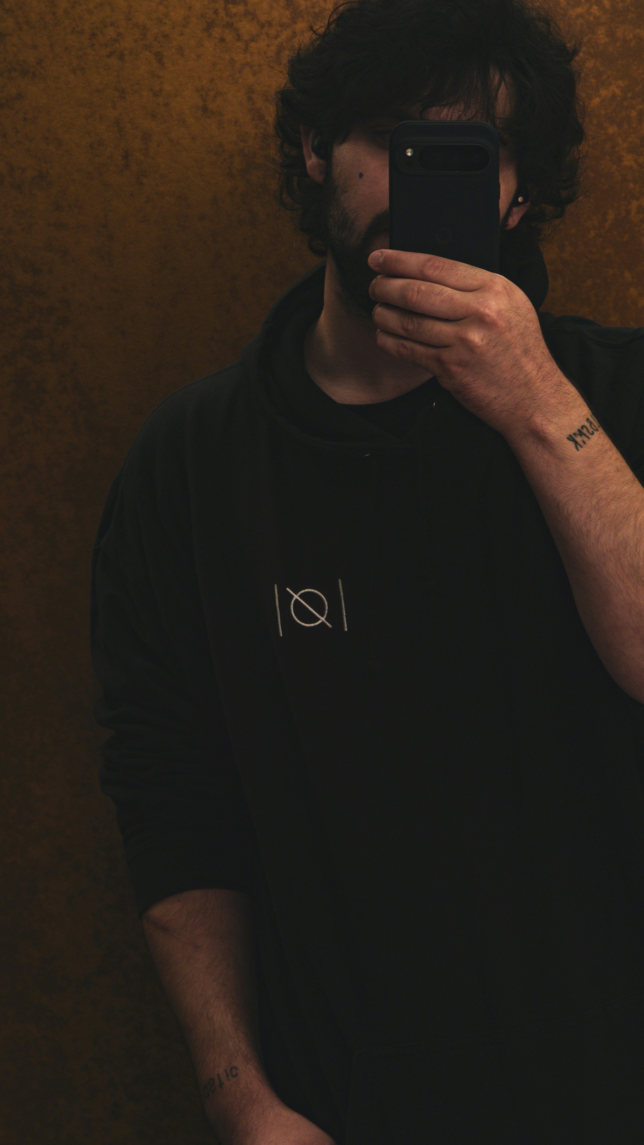 Man in black hoodie taking a selfie with phone