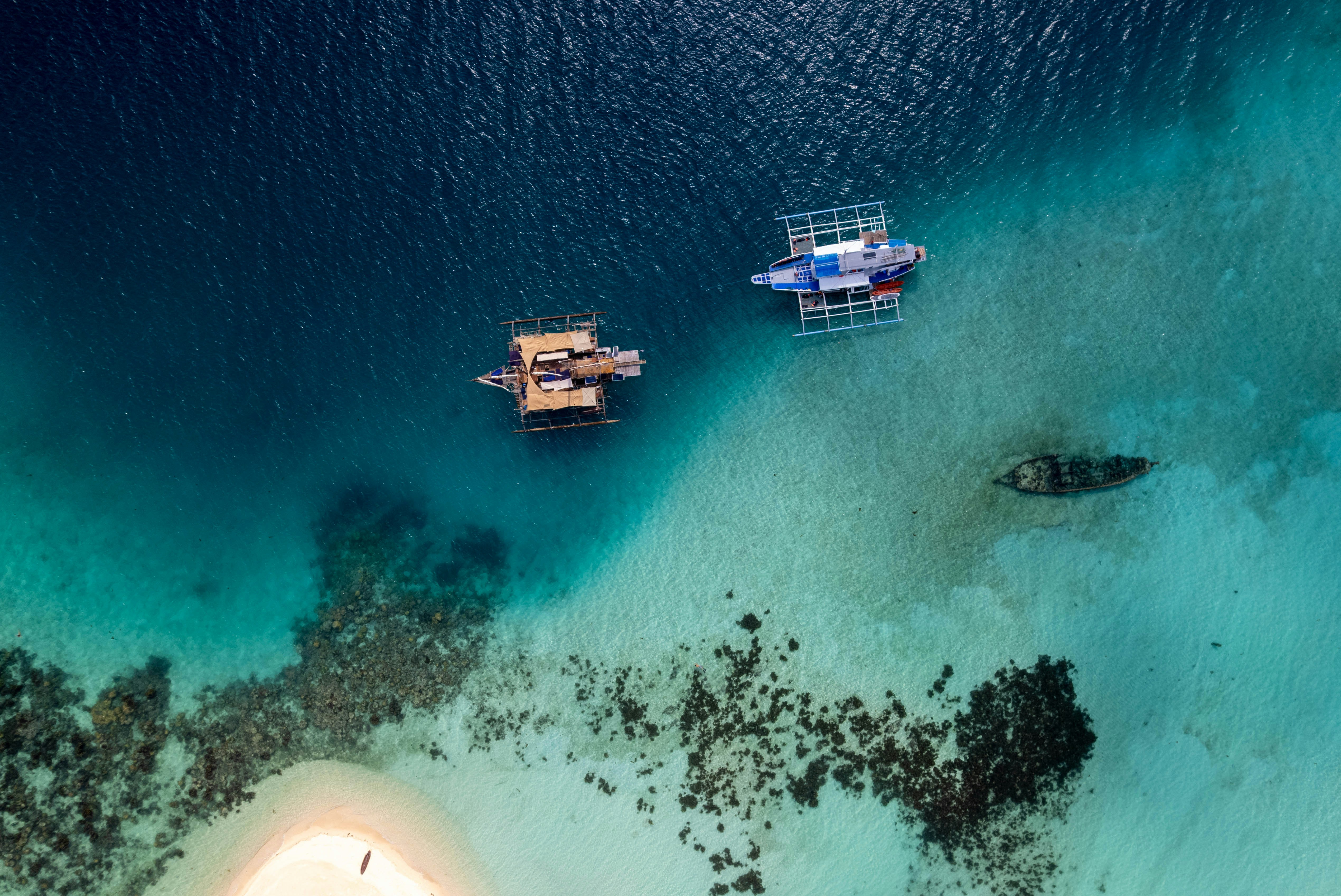 Two boats float on crystal clear tropical waters.