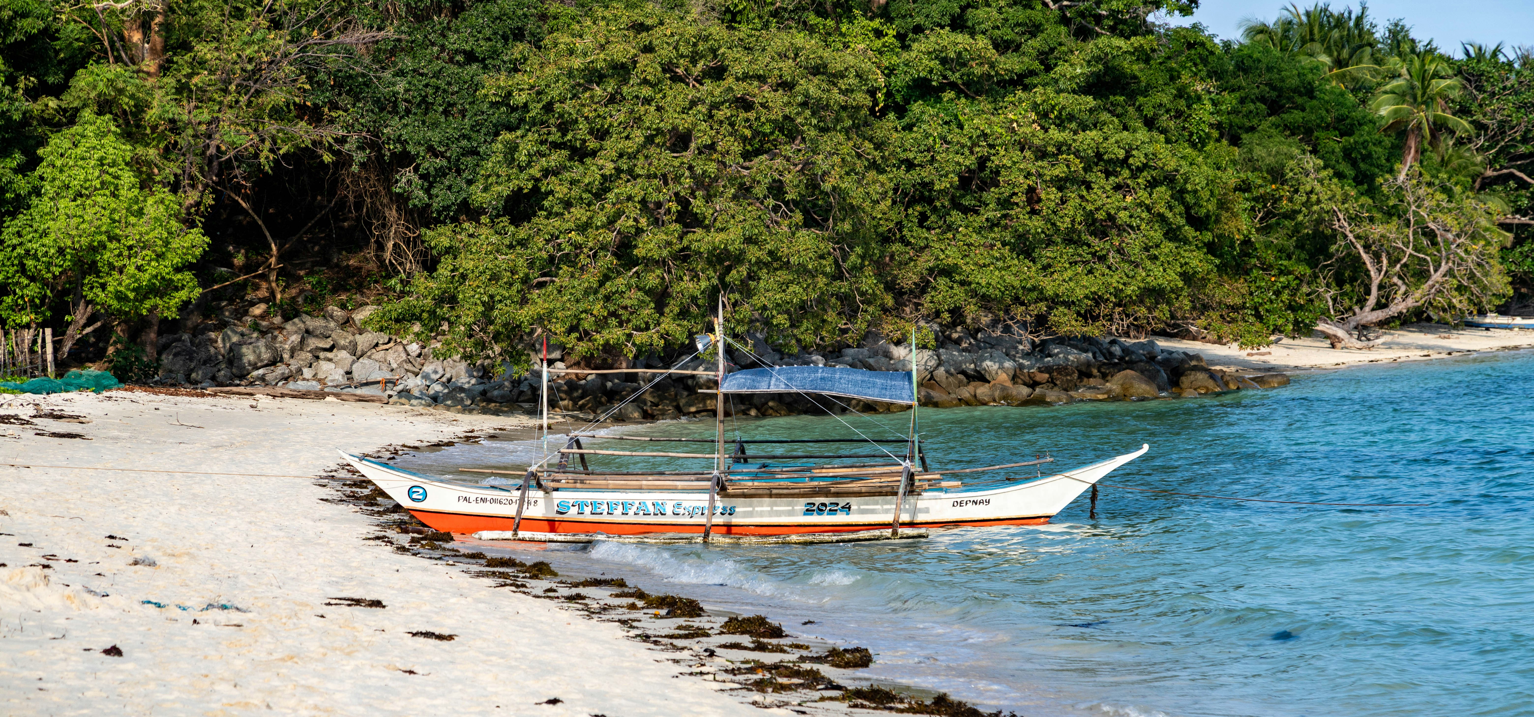 Un bote tradicional filipino descansa en una orilla arenosa. foto ...