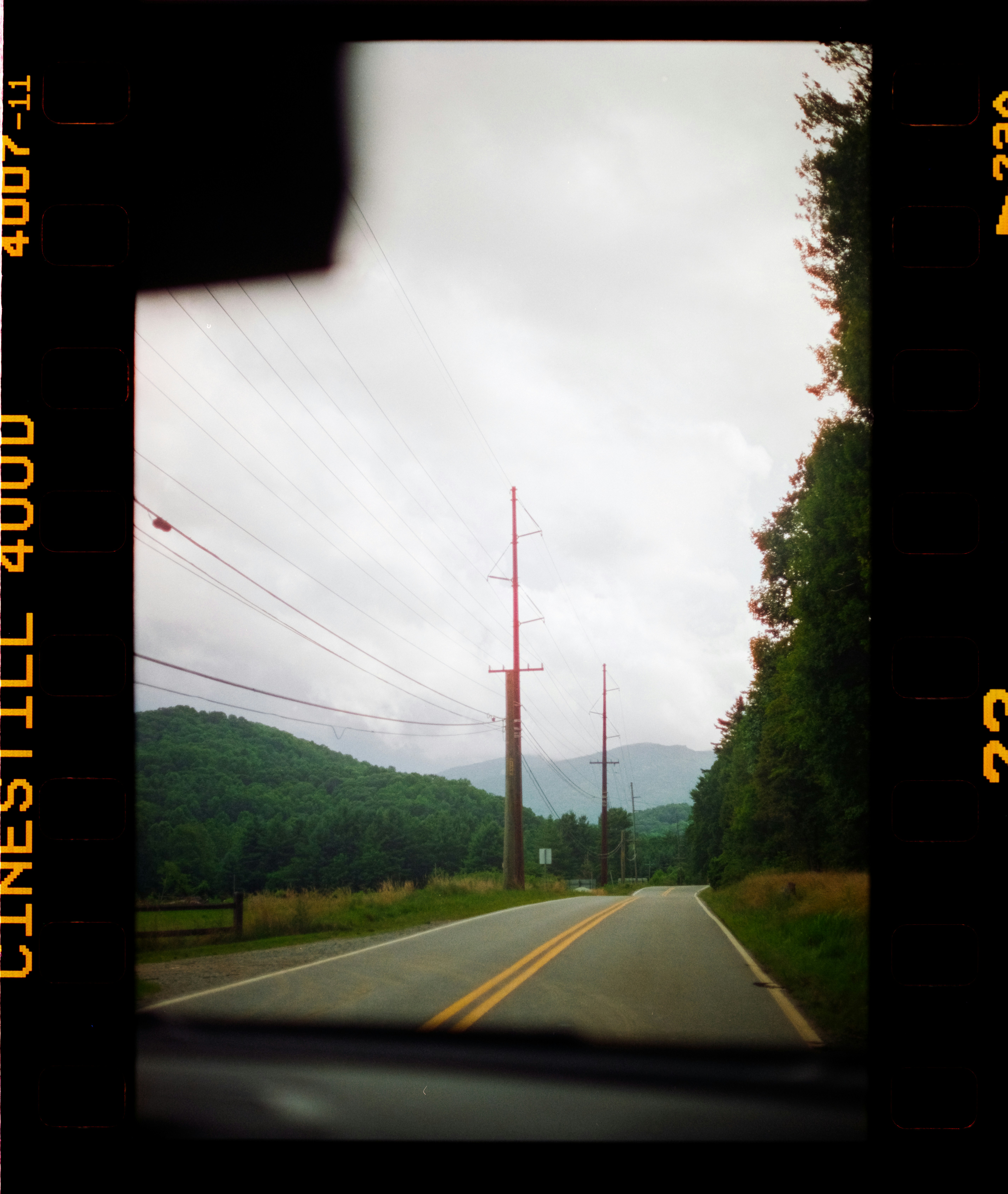 Vanishing Road: Power Poles Guiding a Quiet Drive Through Green Hills