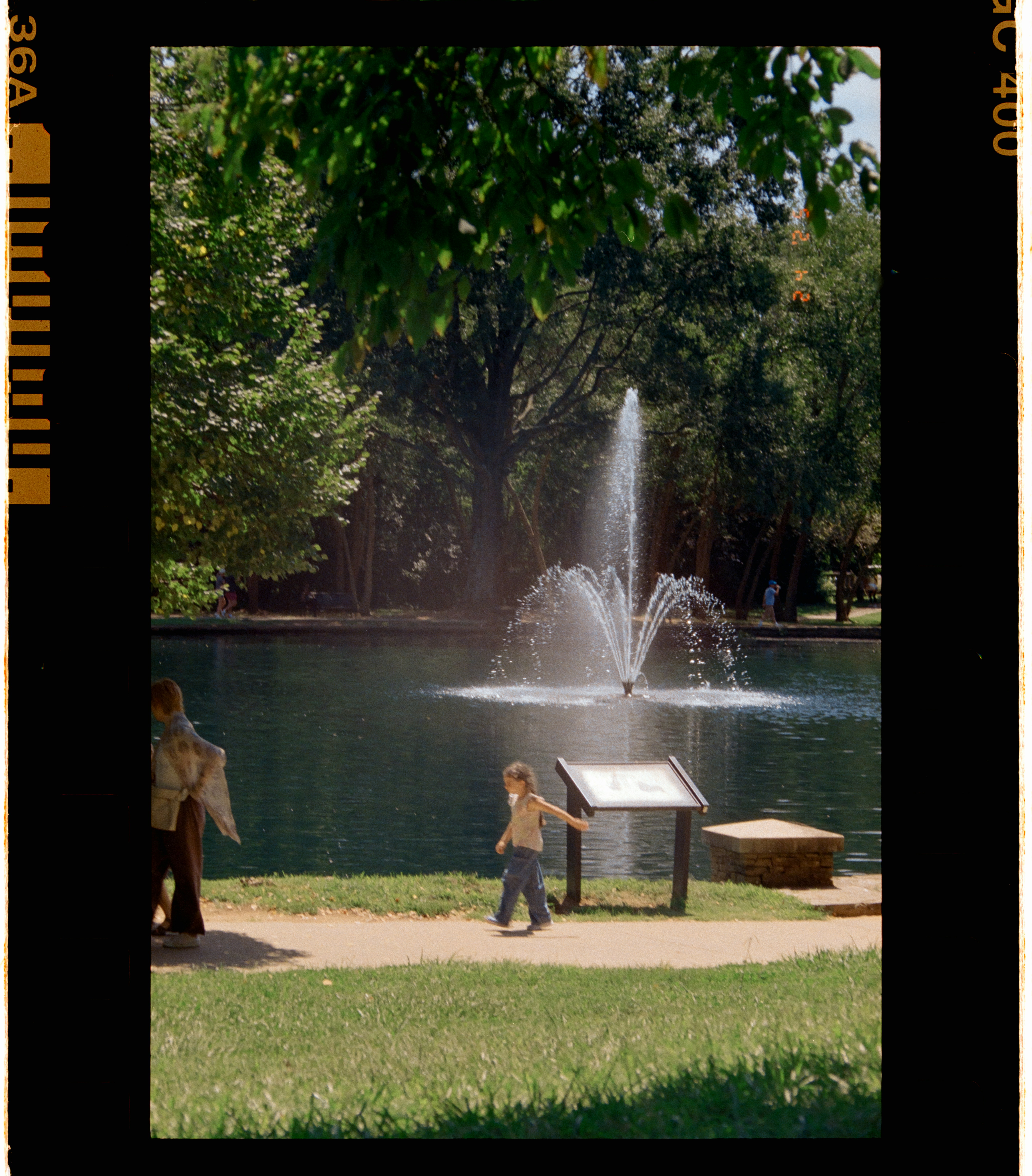 A child plays near a fountain in a park.