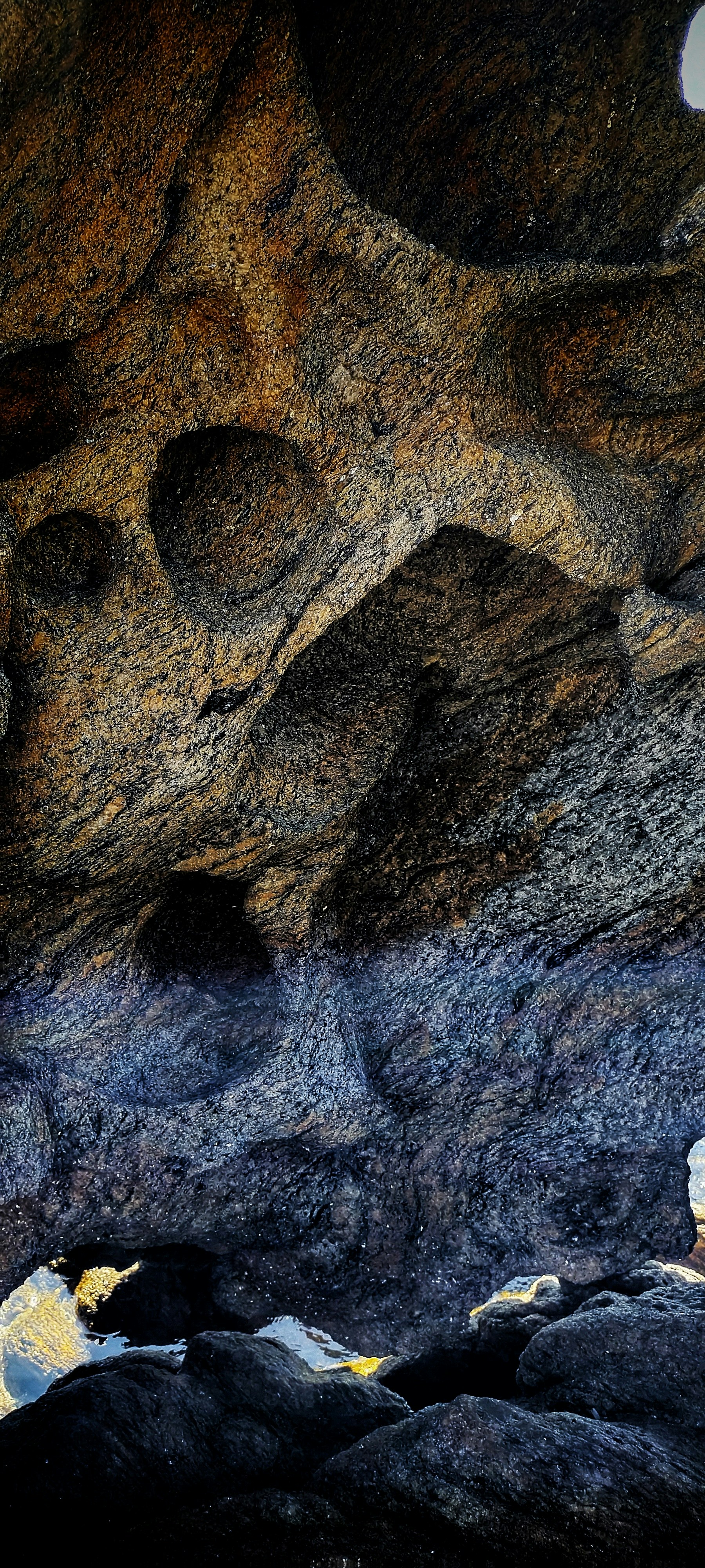 Textured rock formations with natural holes and shadows.