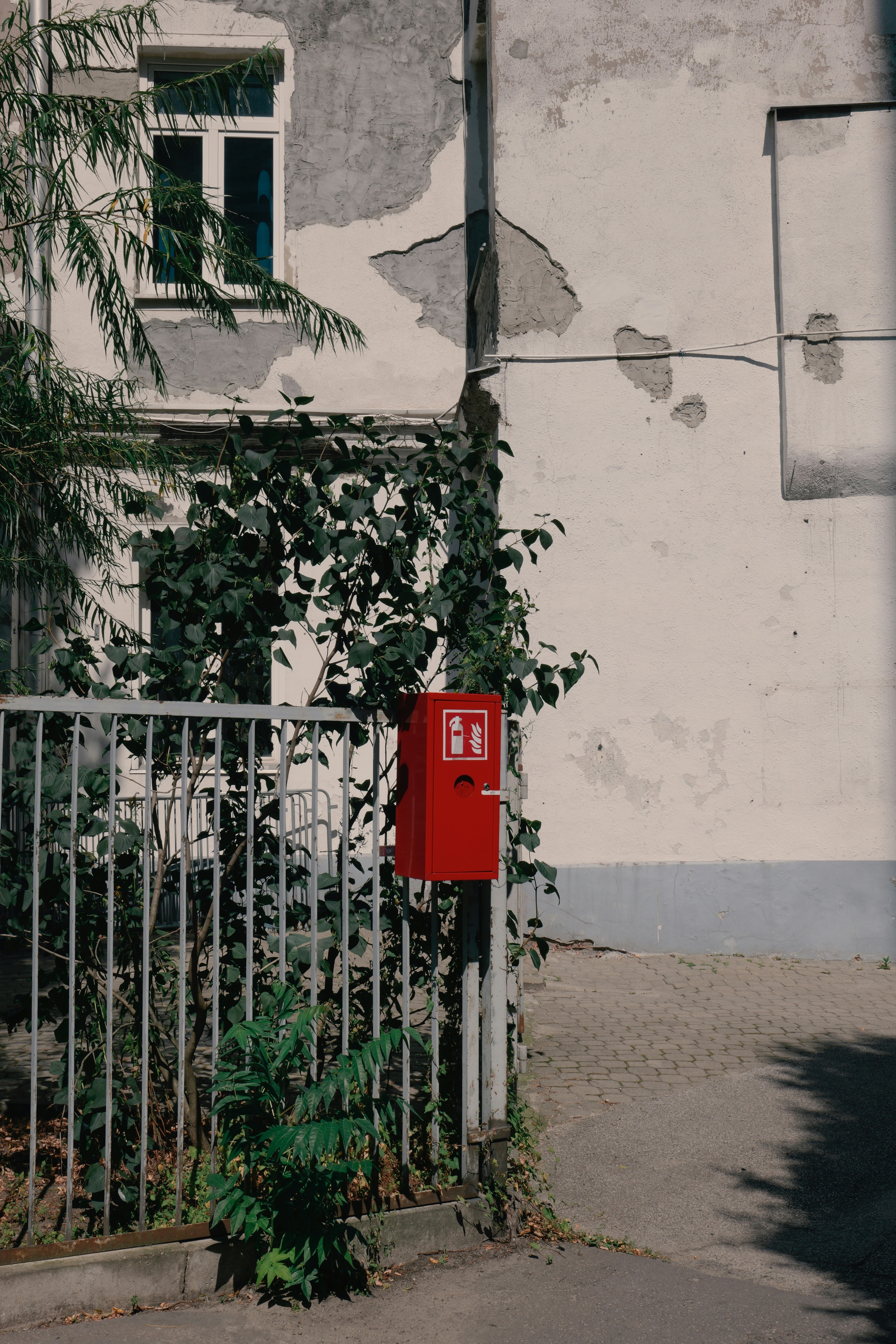 Red box attached to pole near fence and building