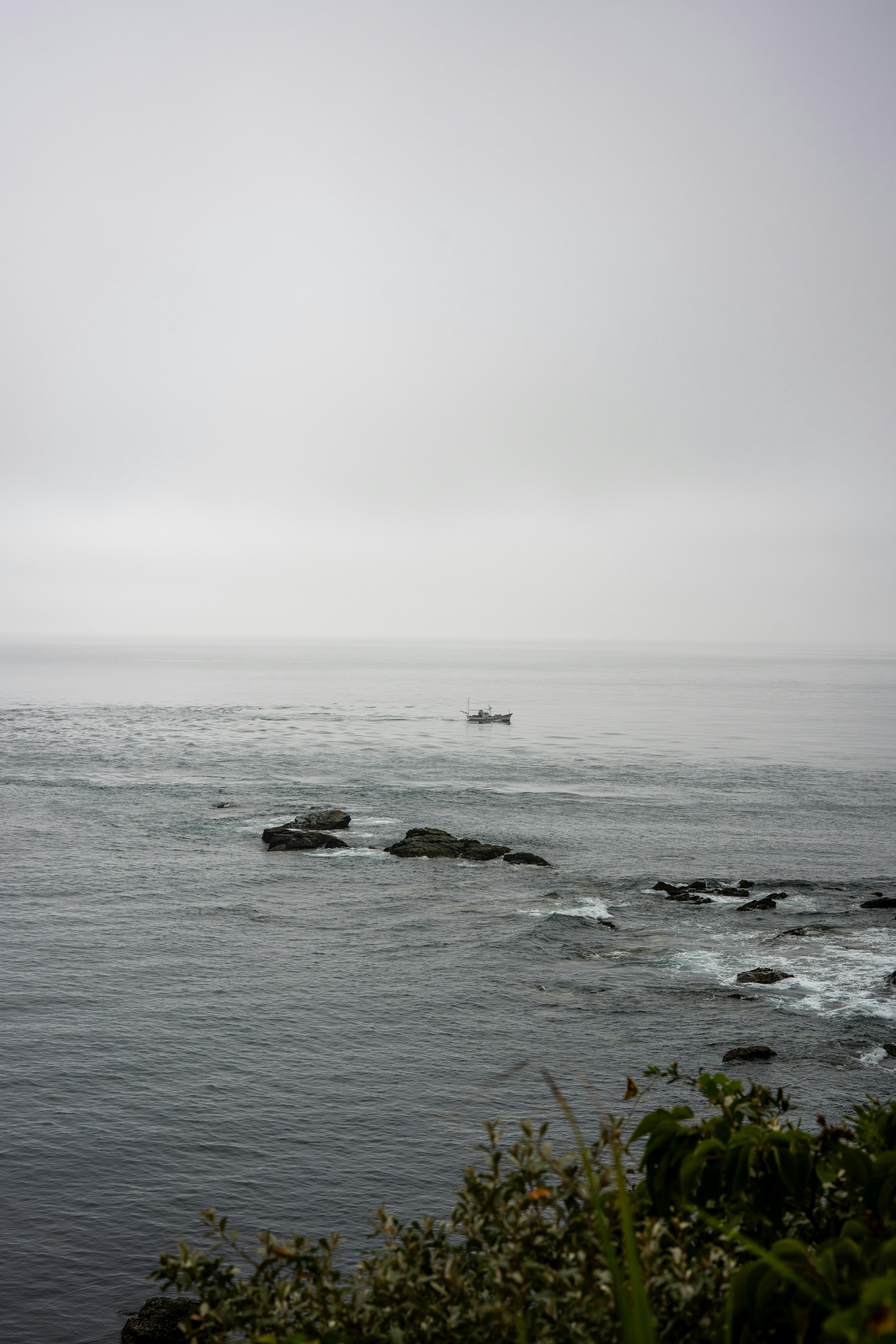 Small boat on a vast, foggy ocean