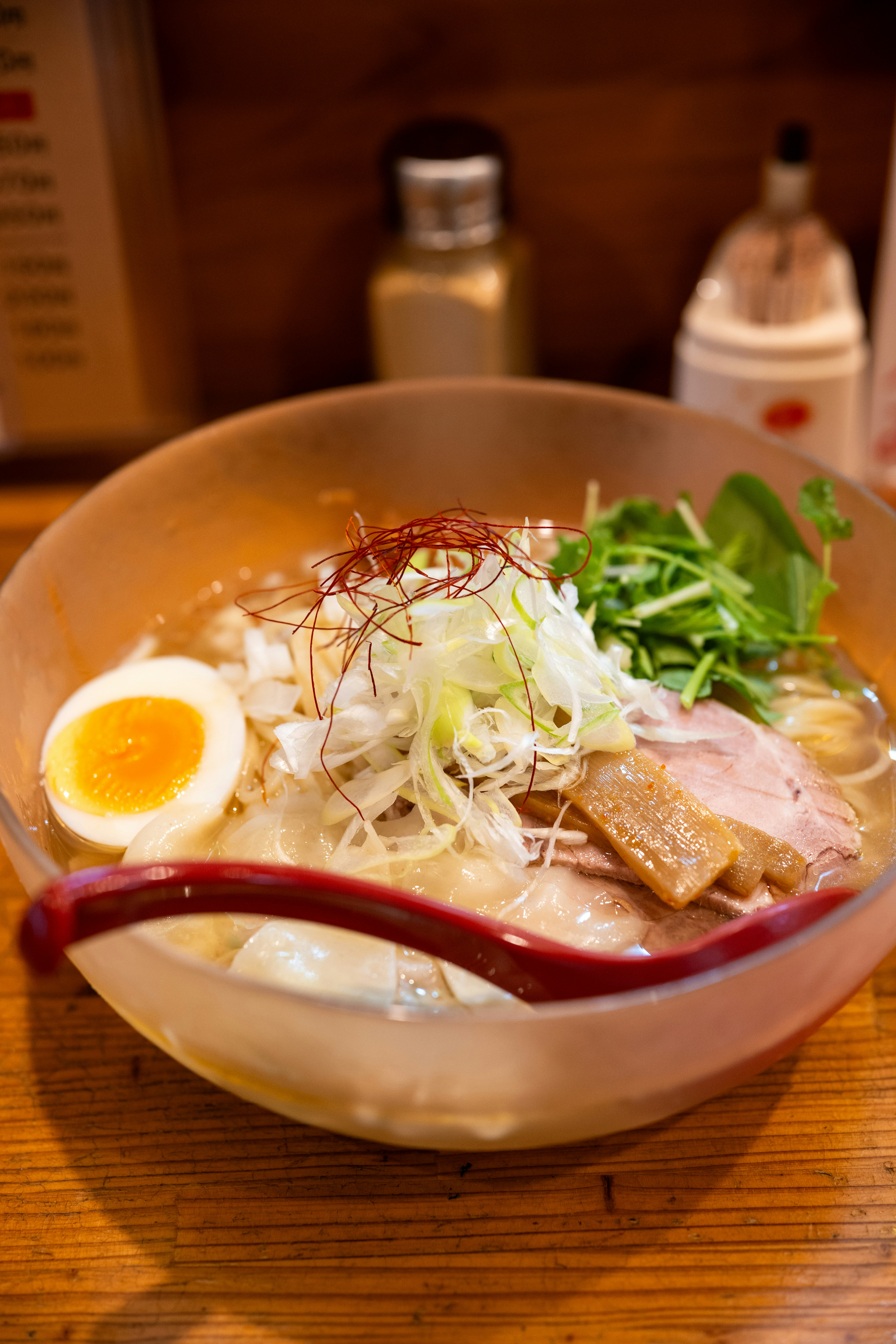 A bowl of ramen with egg, pork, and vegetables.