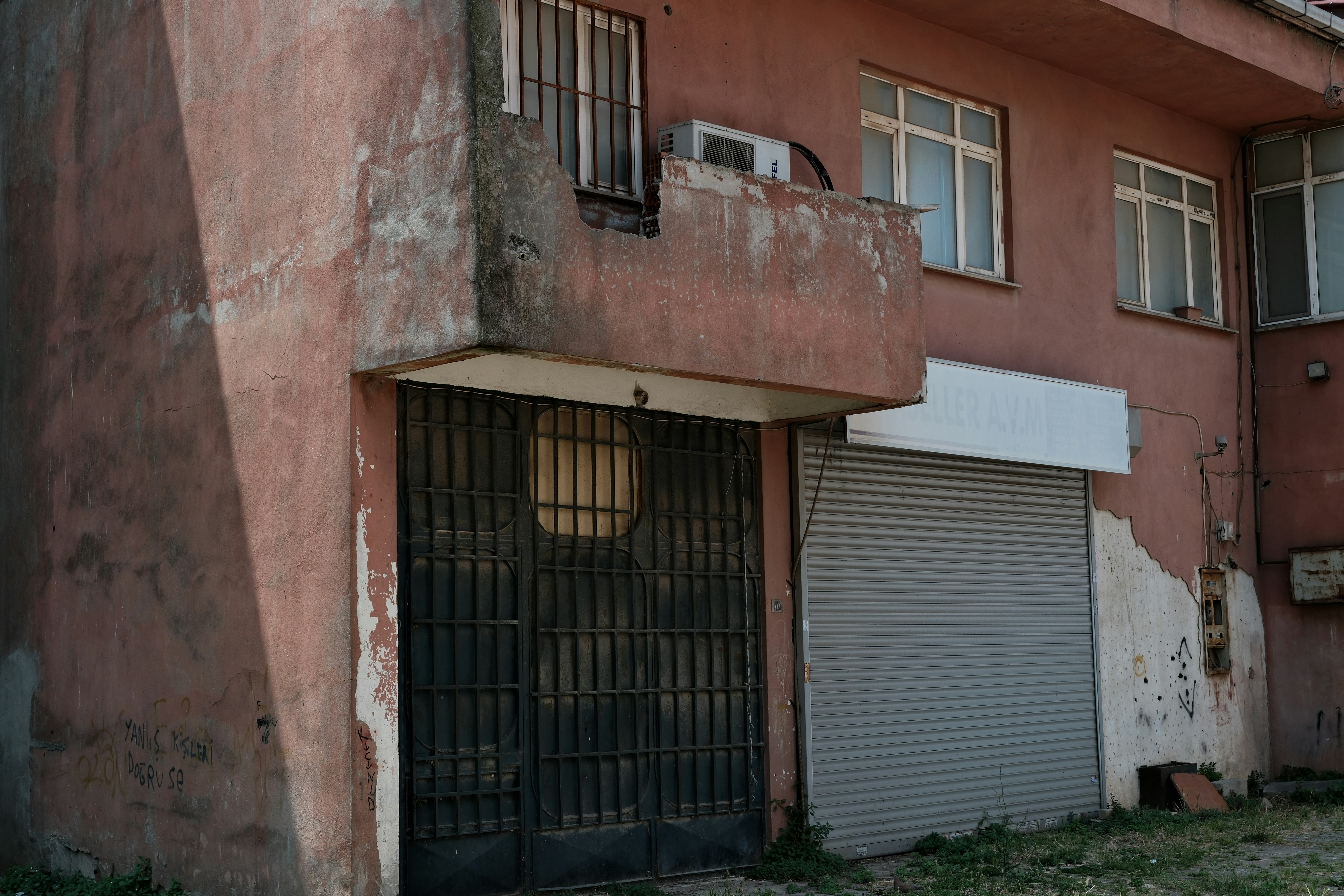 Old building in one of Istanbul's neighbourhoods. | A weathered building with metal gates and shutters.
